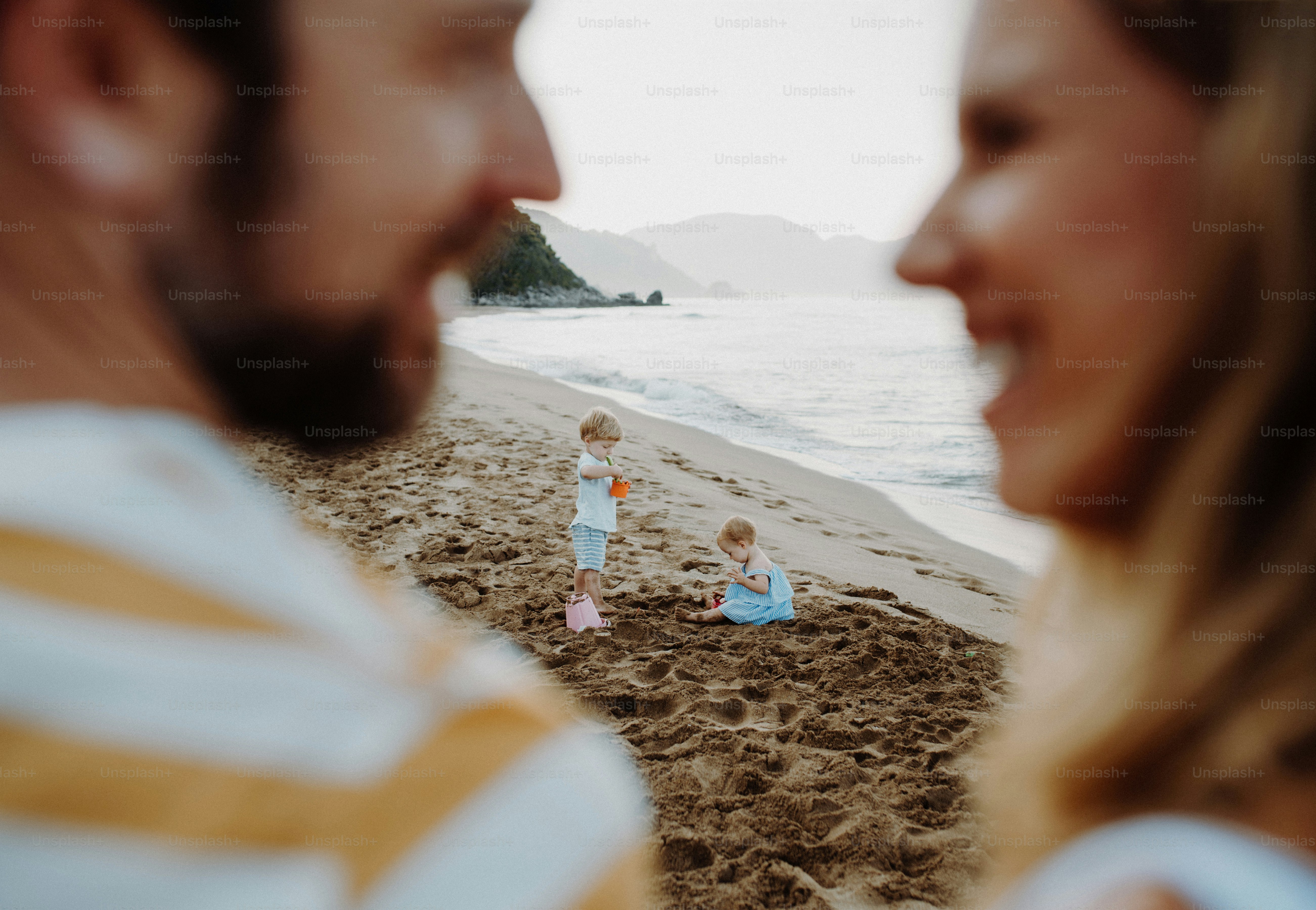 Parents and toddler children playing on sand beach on summer family ...