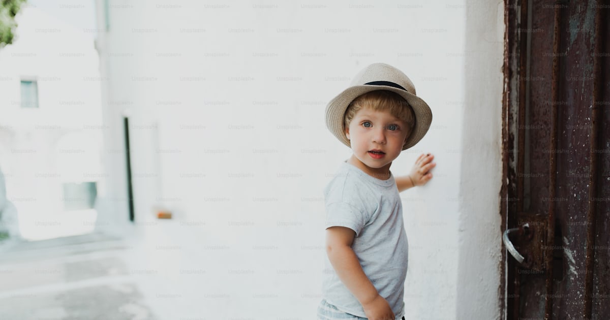 夏休みに町の家のそばに立つ帽子をかぶった小さな幼児の男の子。スペースをコピーします。の写真 帽子 Unsplashの写真