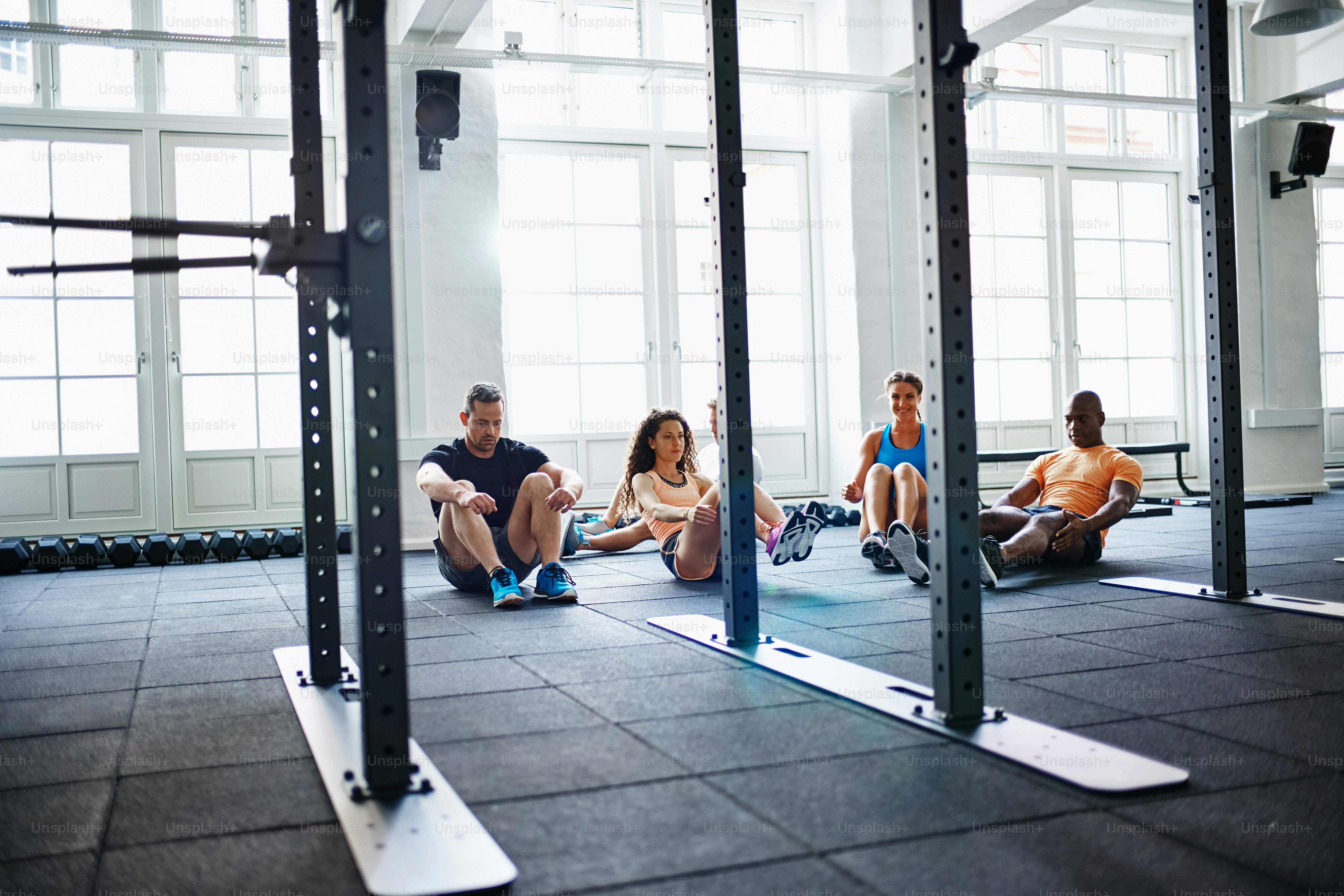 Diverse group of friends doing crunches while working out together on ...