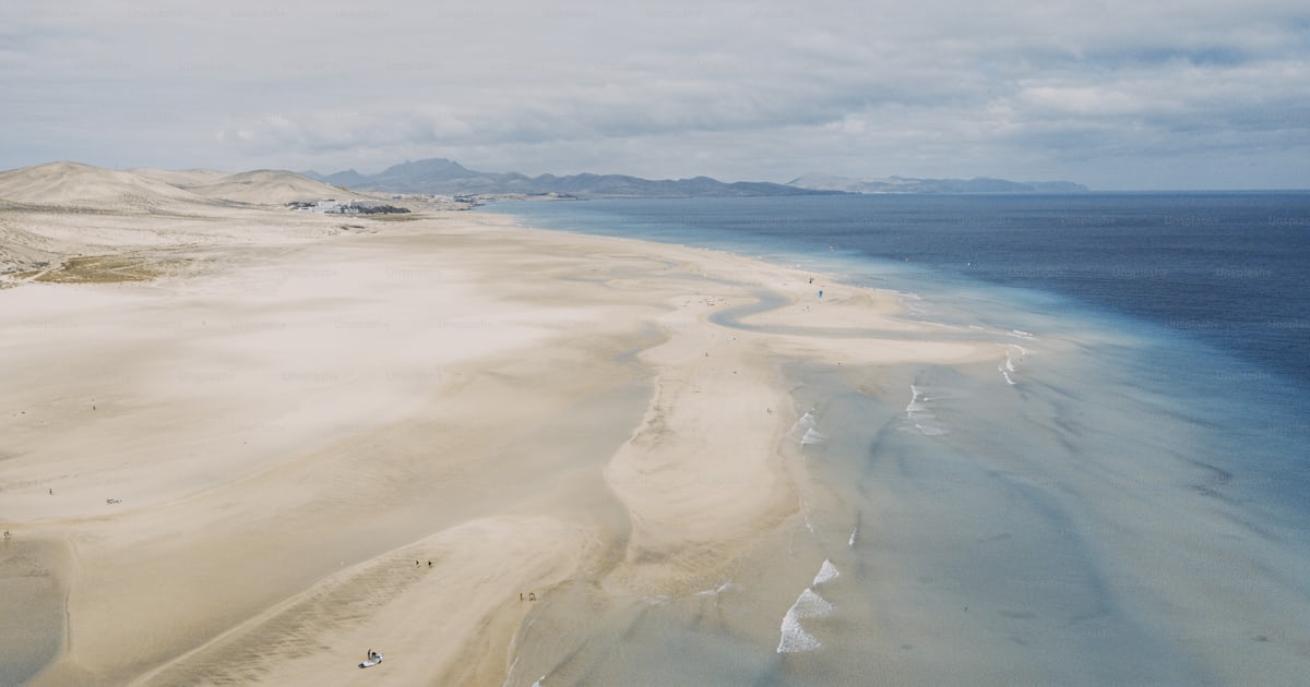 素晴らしい熱帯のビーチと青い透明な海の水。地平線と空と山々を背景に、海岸線と素晴らしい海の景色を空から見た風景。夏の旅行の写真 自然