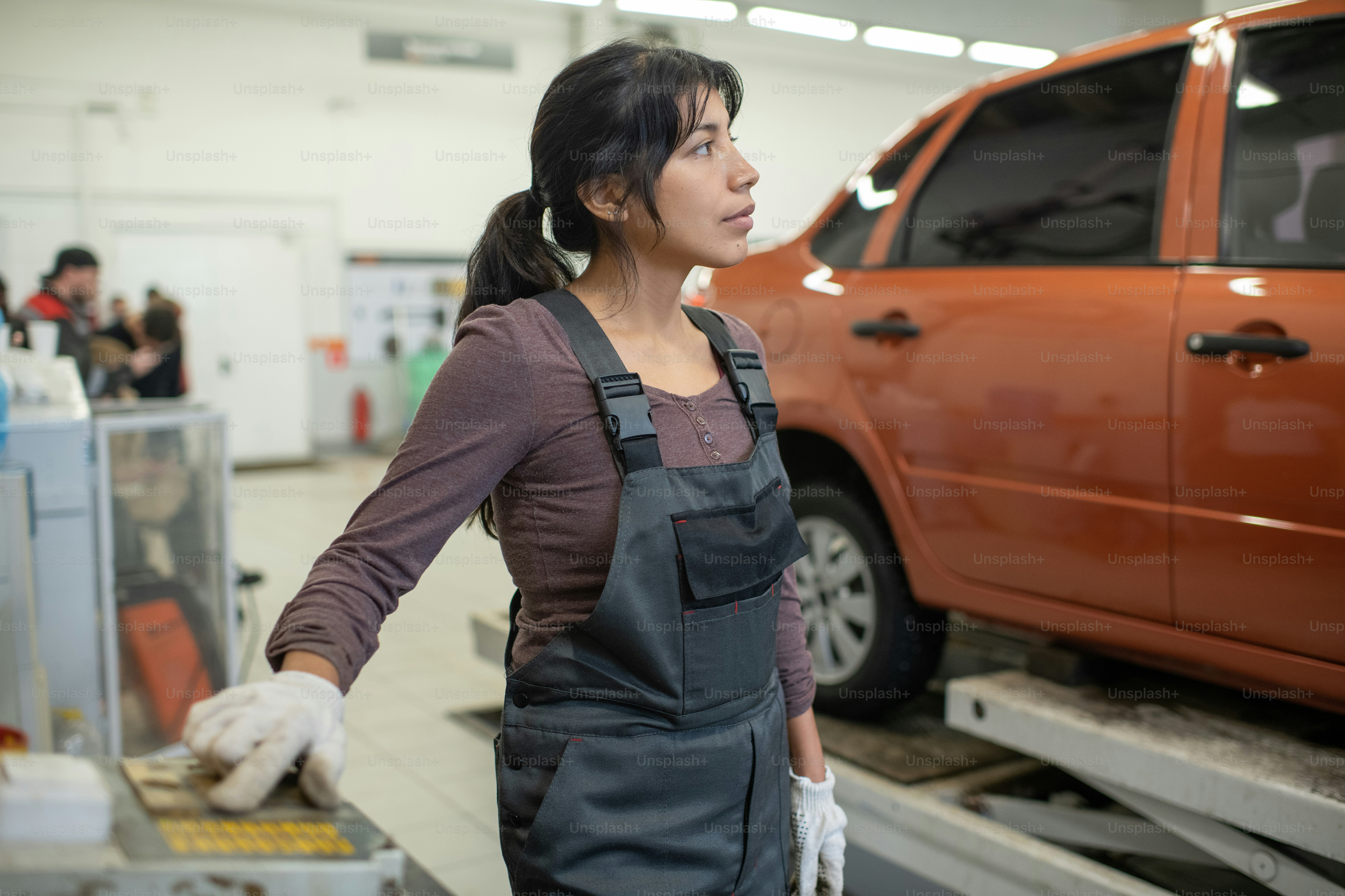 Young confident Hispanic female in overalls and gloves working in ...