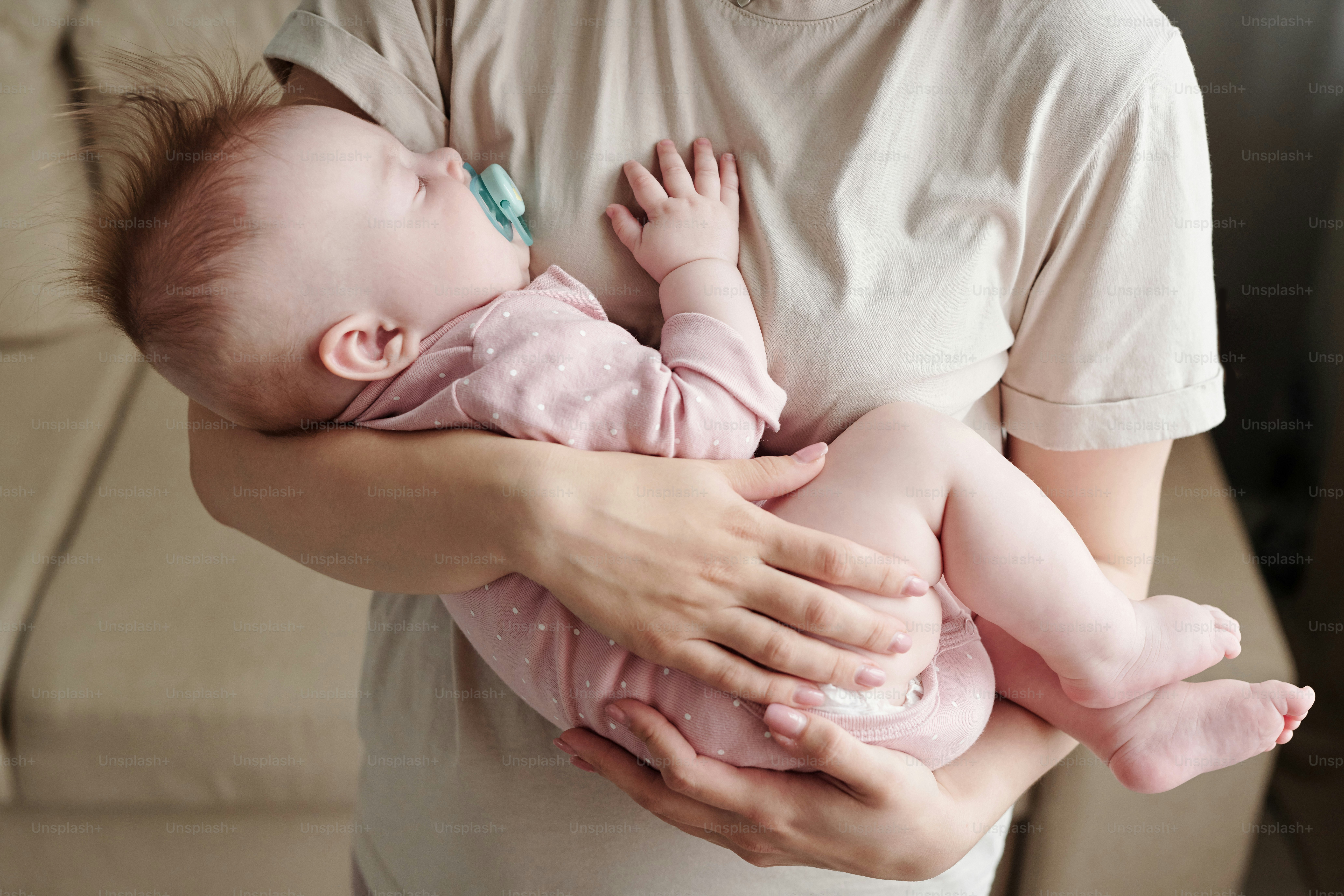 Cute tired baby girl with pacifier sleeping on hands of her careful ...