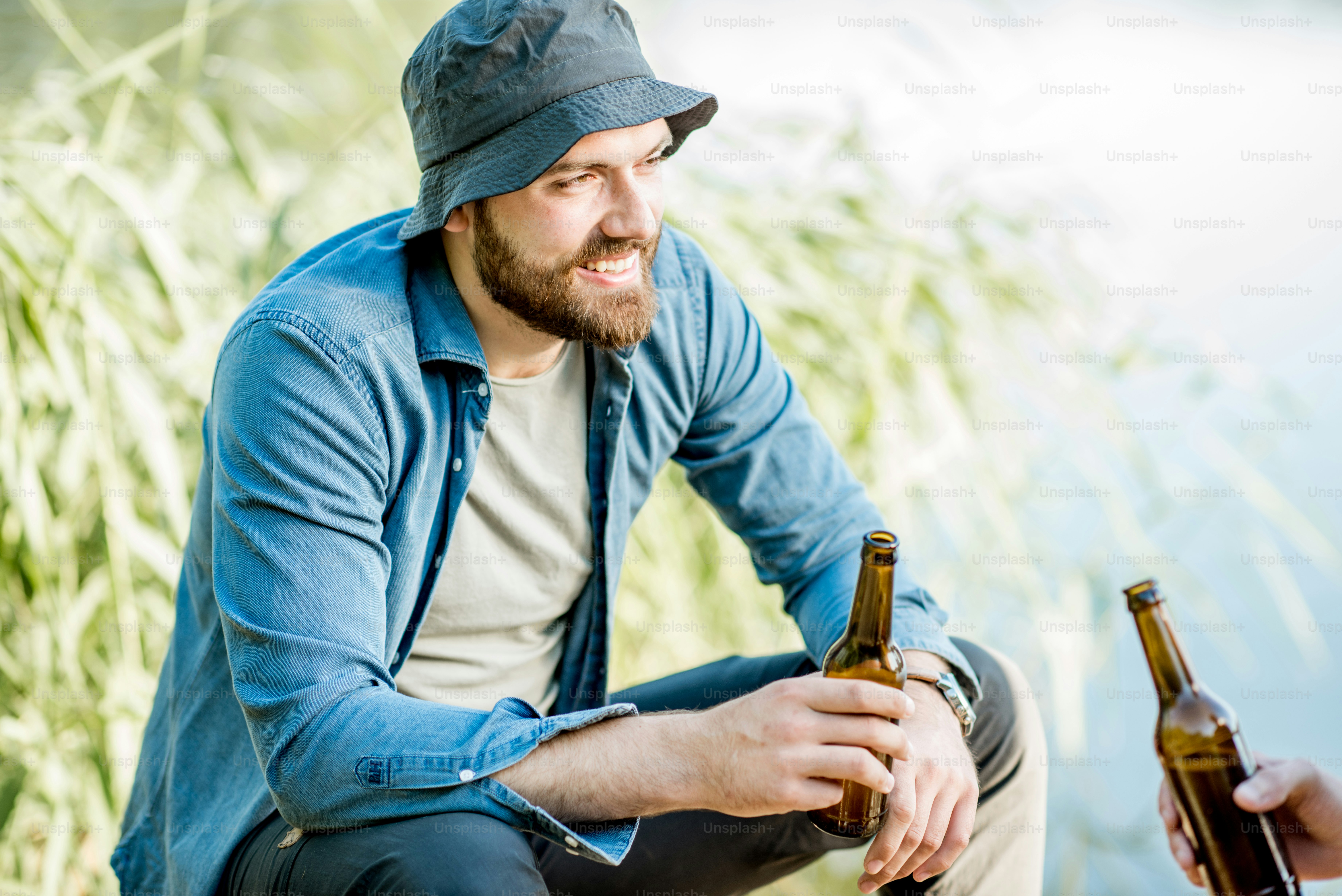 Portrait of a handsome fishermen sitting with beer during the picnic on ...