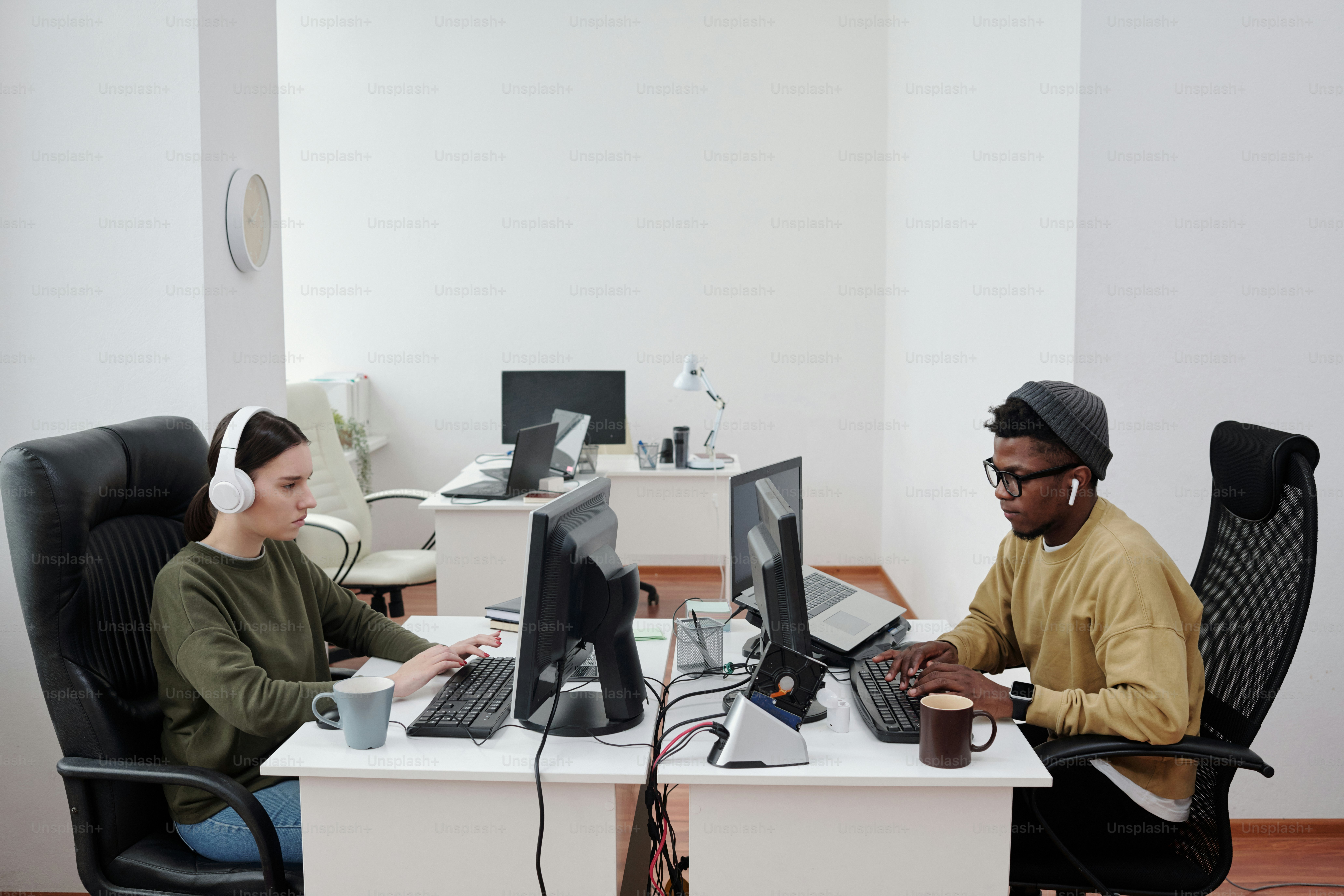 Side view of two young intercultural programmers working in front of ...