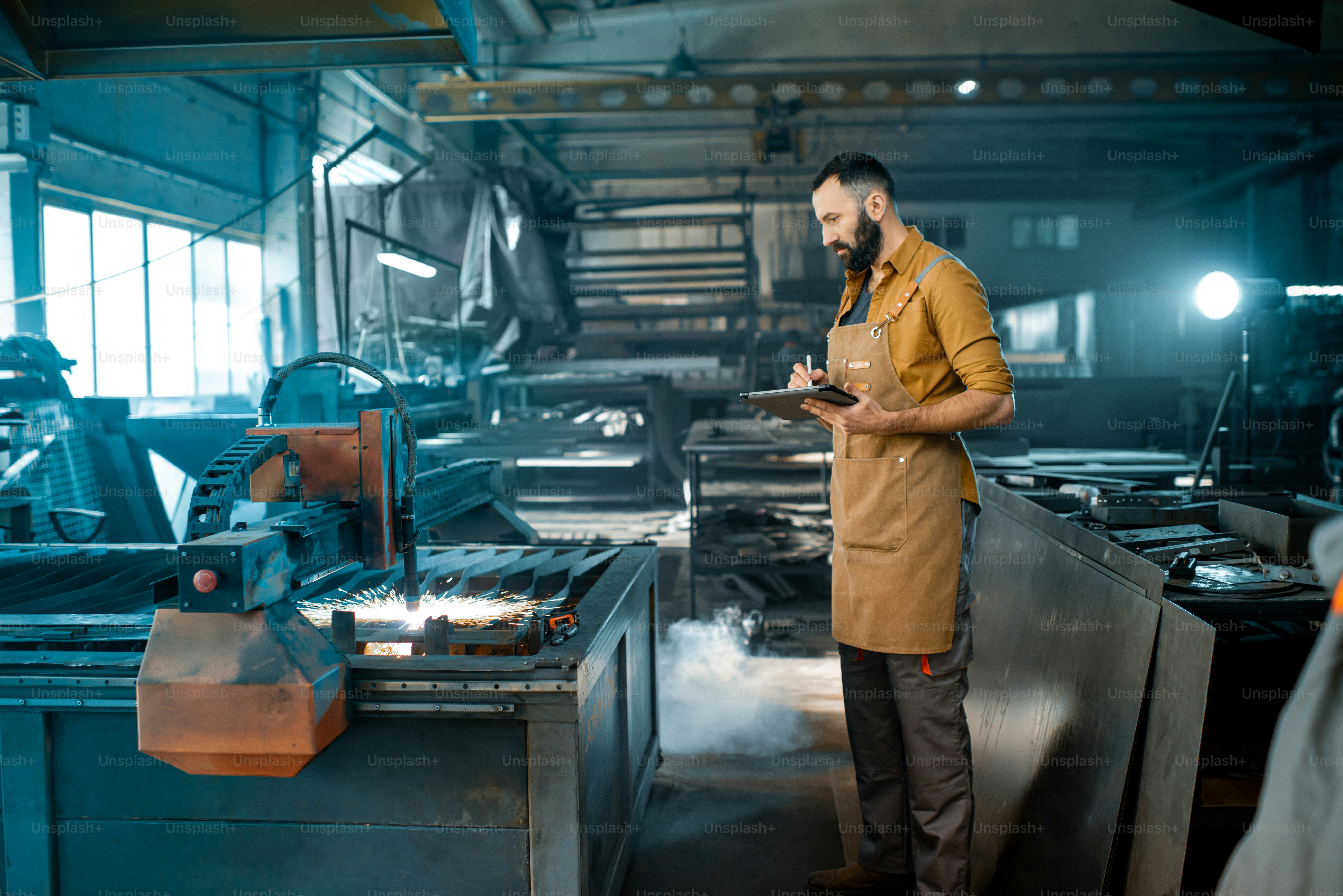 Heavy industry worker controlling the process of metal cutting. High ...