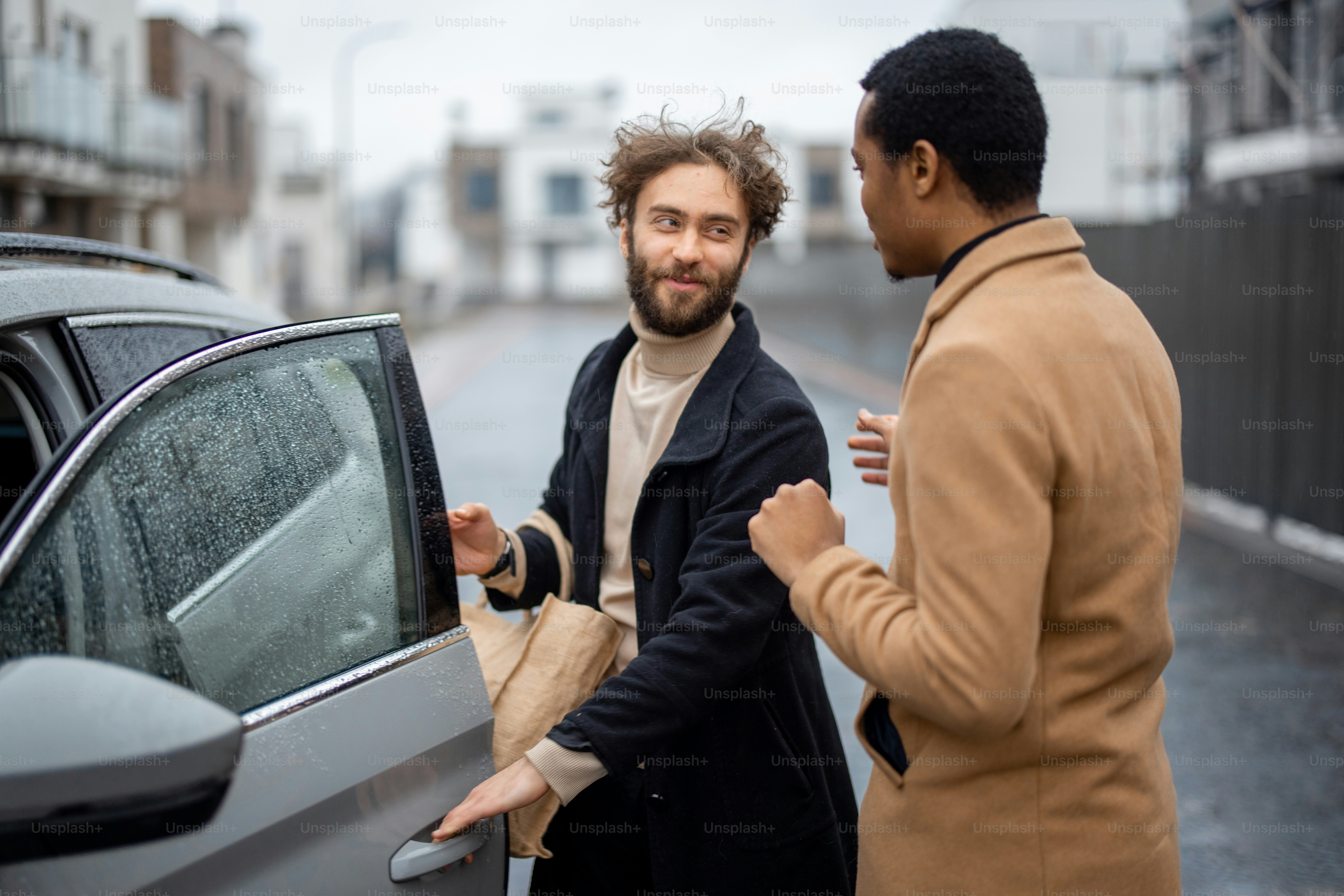 Two men flirting or having a close conversation while opening car door on the street. Concept of ...