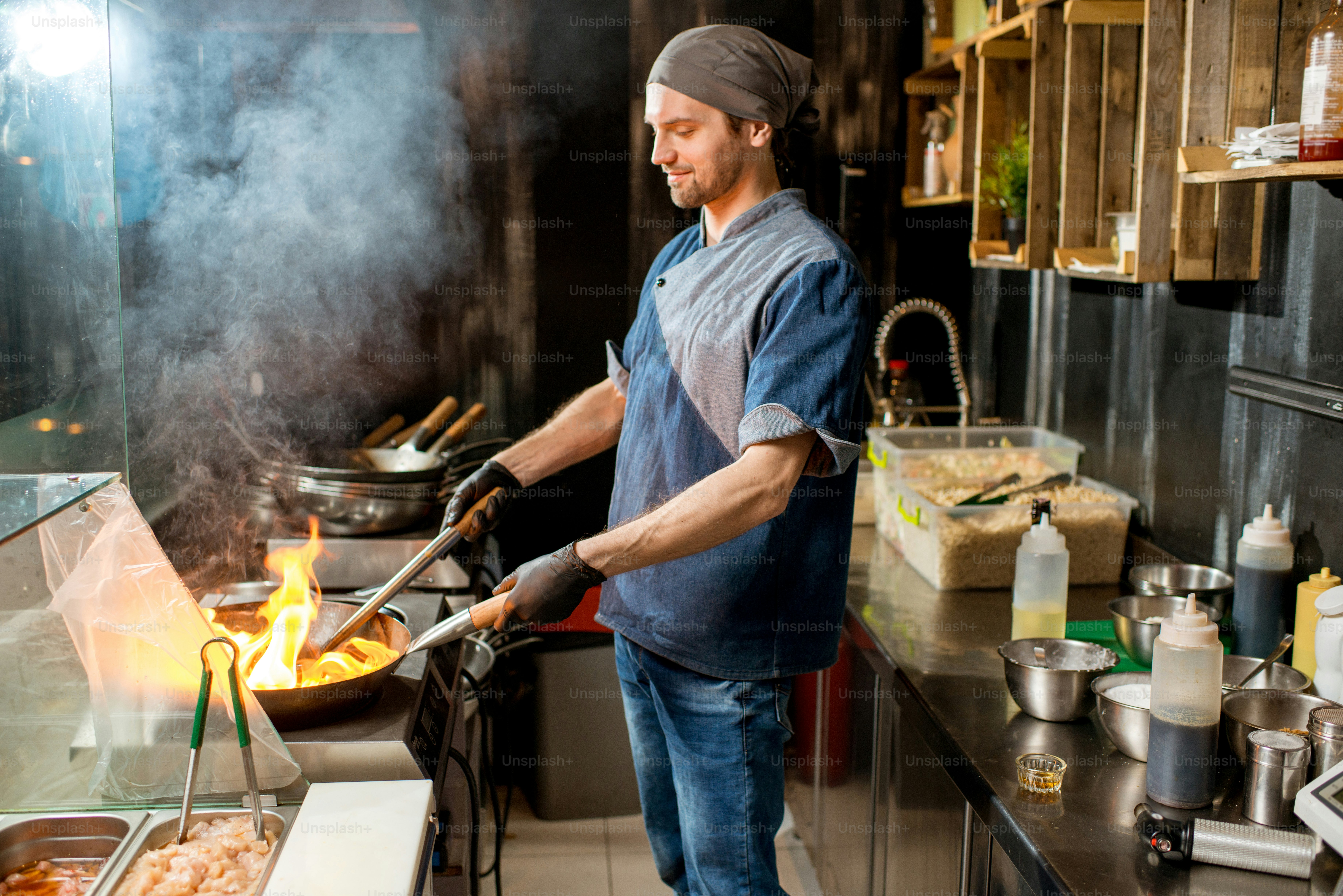 Caucasian chief cook cooking with wok pan on the asian restaurant ...