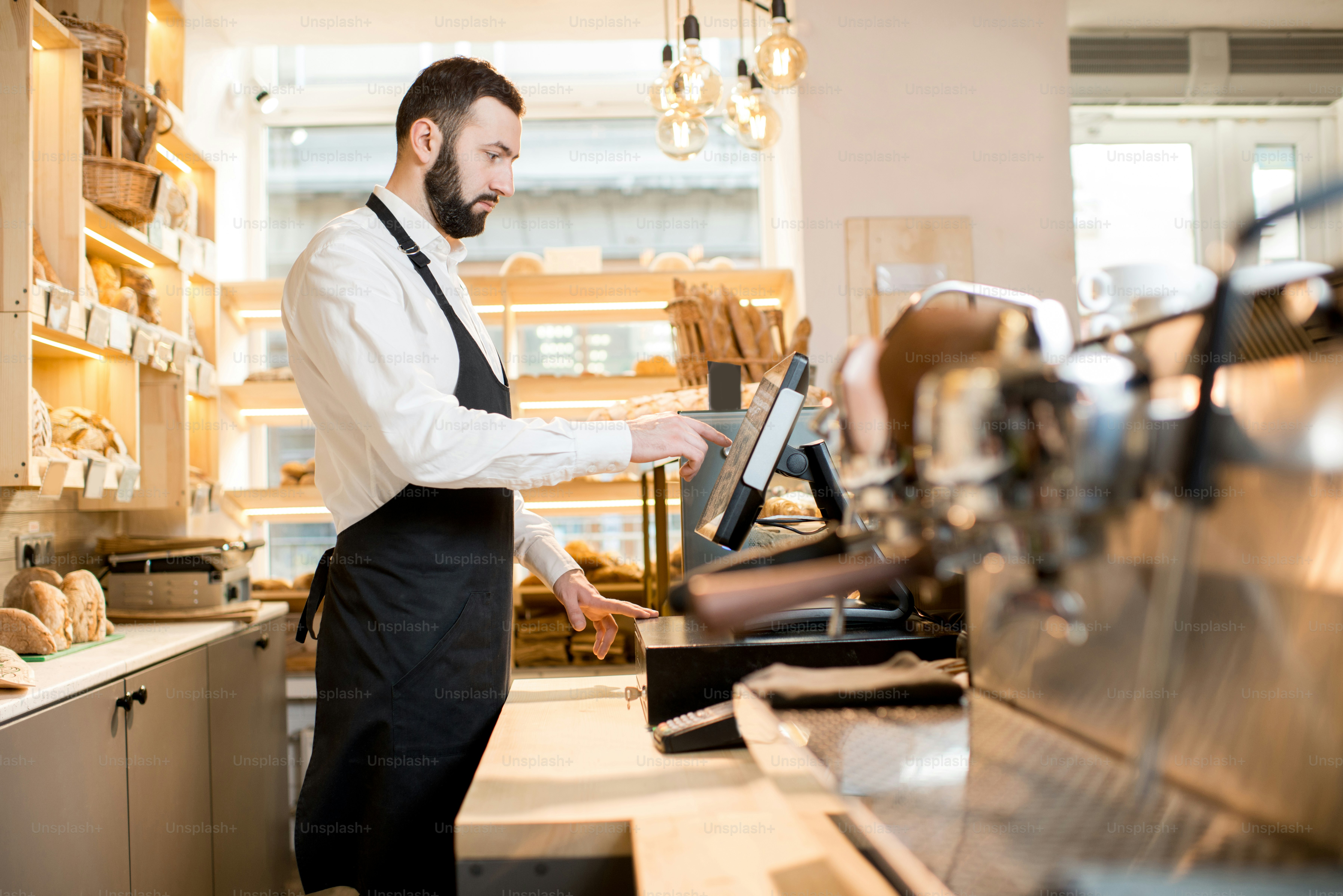 Handsome bread seller working in the store with bakery products photo ...