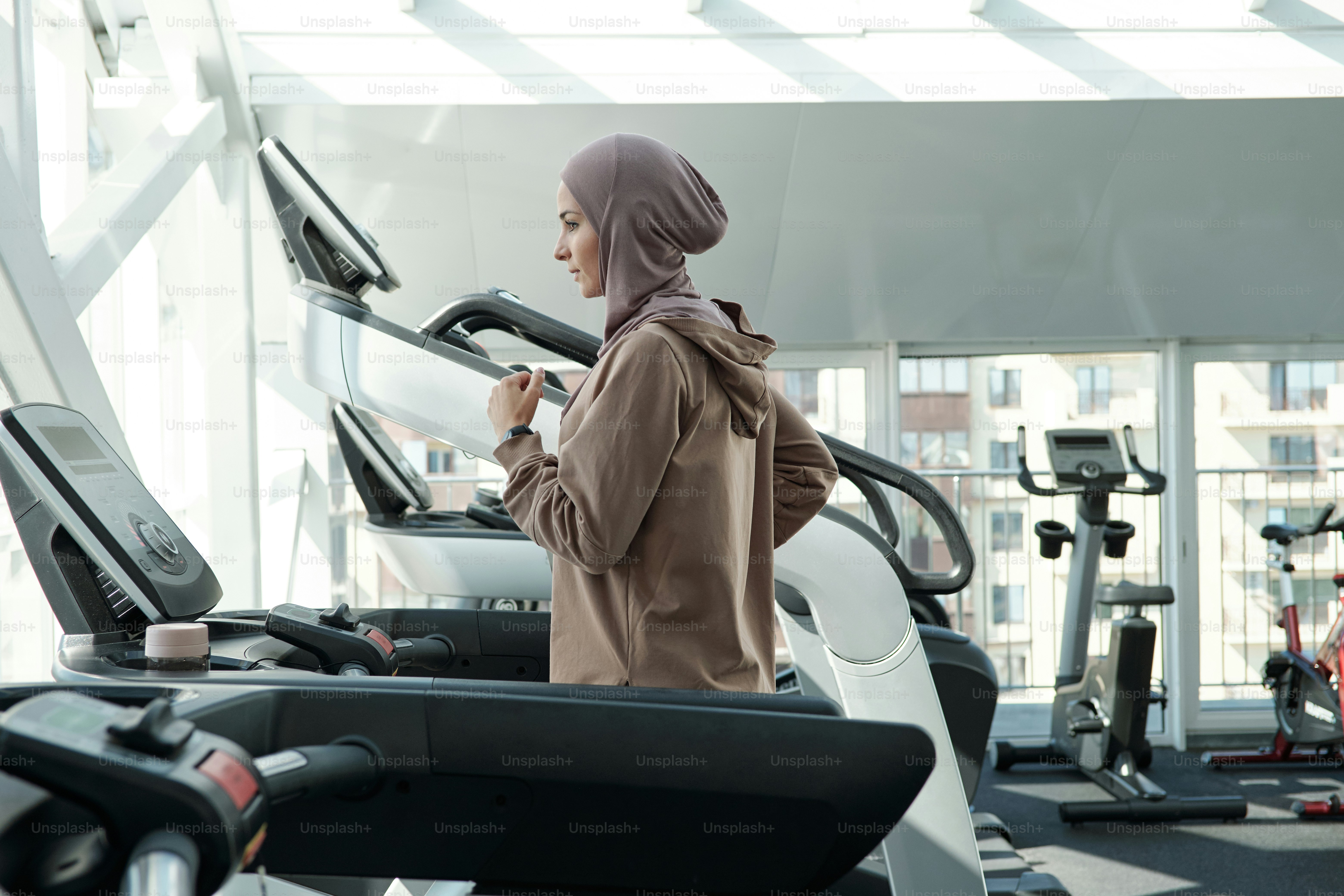 Horizontal long shot of modern Muslim woman wearing hijab exercising in ...