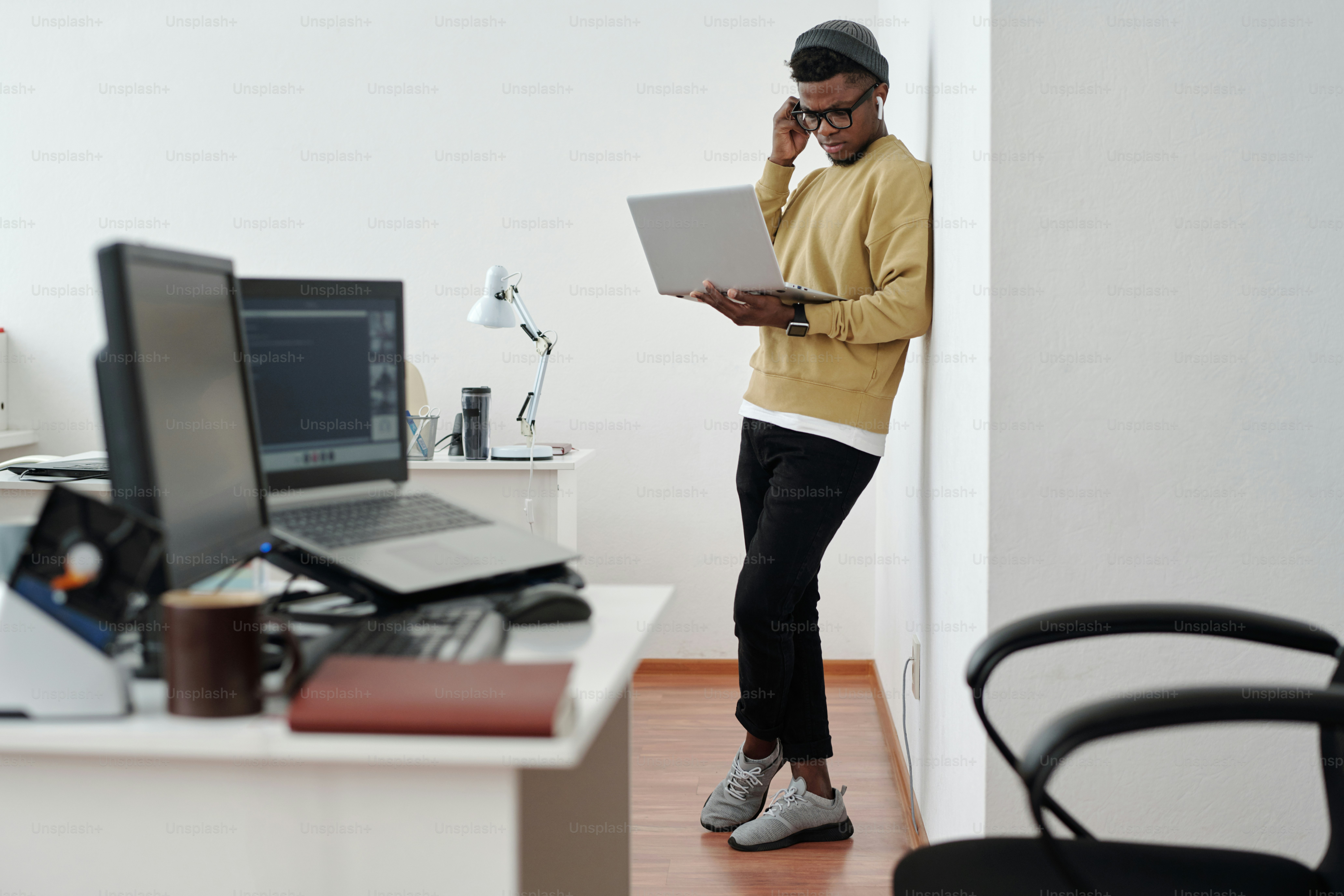 Young serious African American male programmer with laptop standing by ...