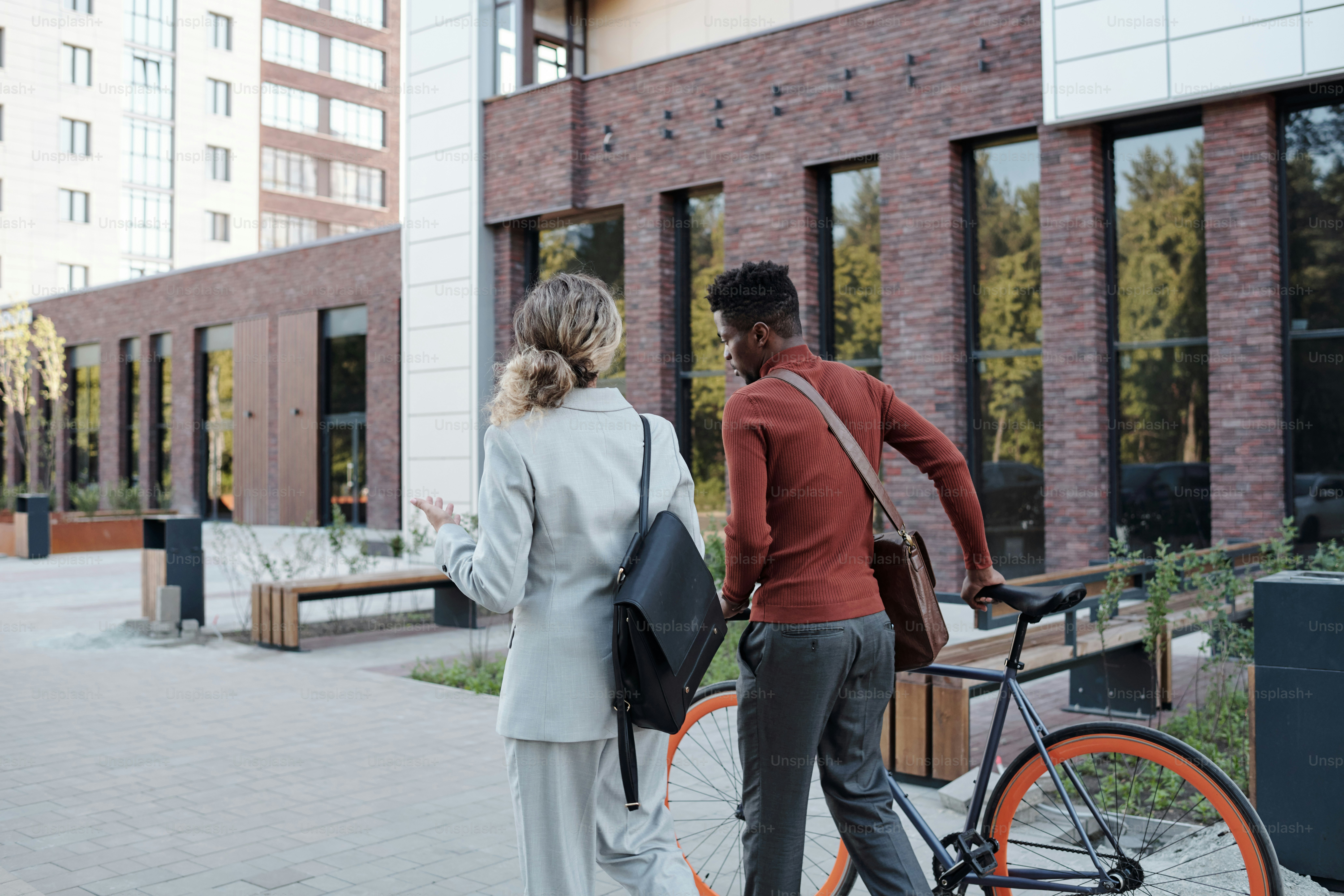 Rear view of two colleagues moving along park in urban environment ...