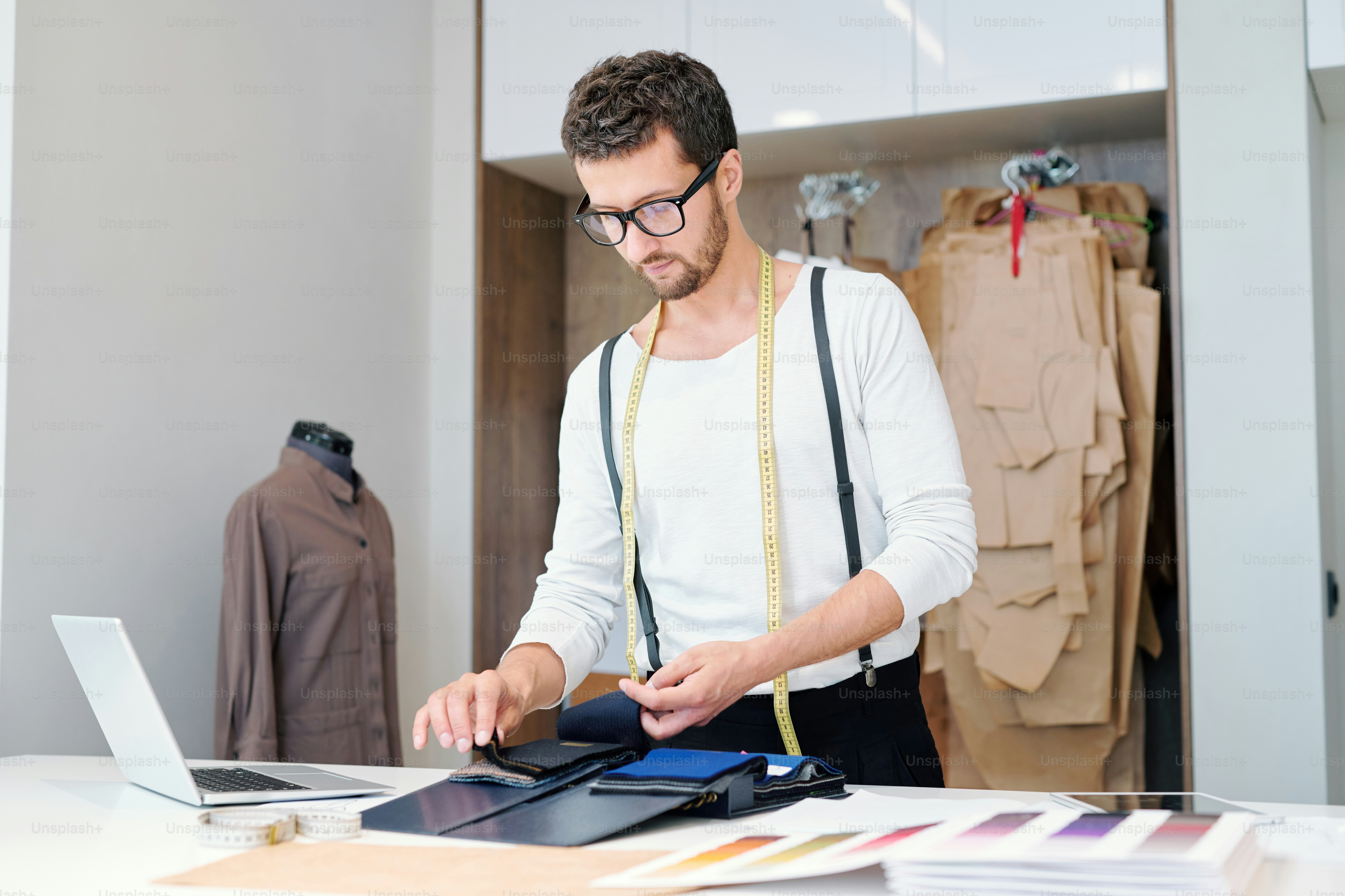 Foto Joven sastre con ropa informal mirando muestras textiles mientras ...