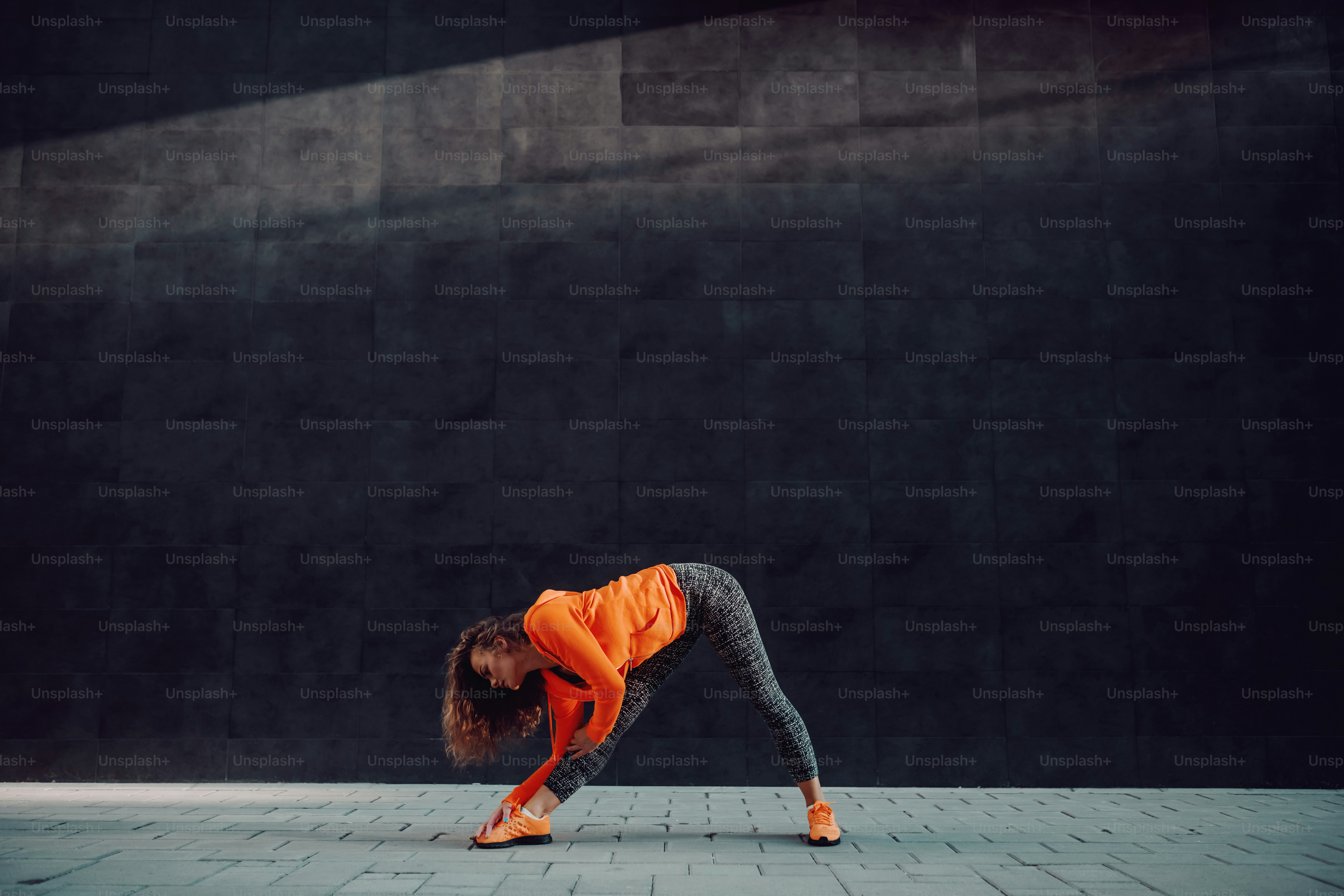 Beautiful slim caucasian sporty woman in sportswear and with curly hair ...