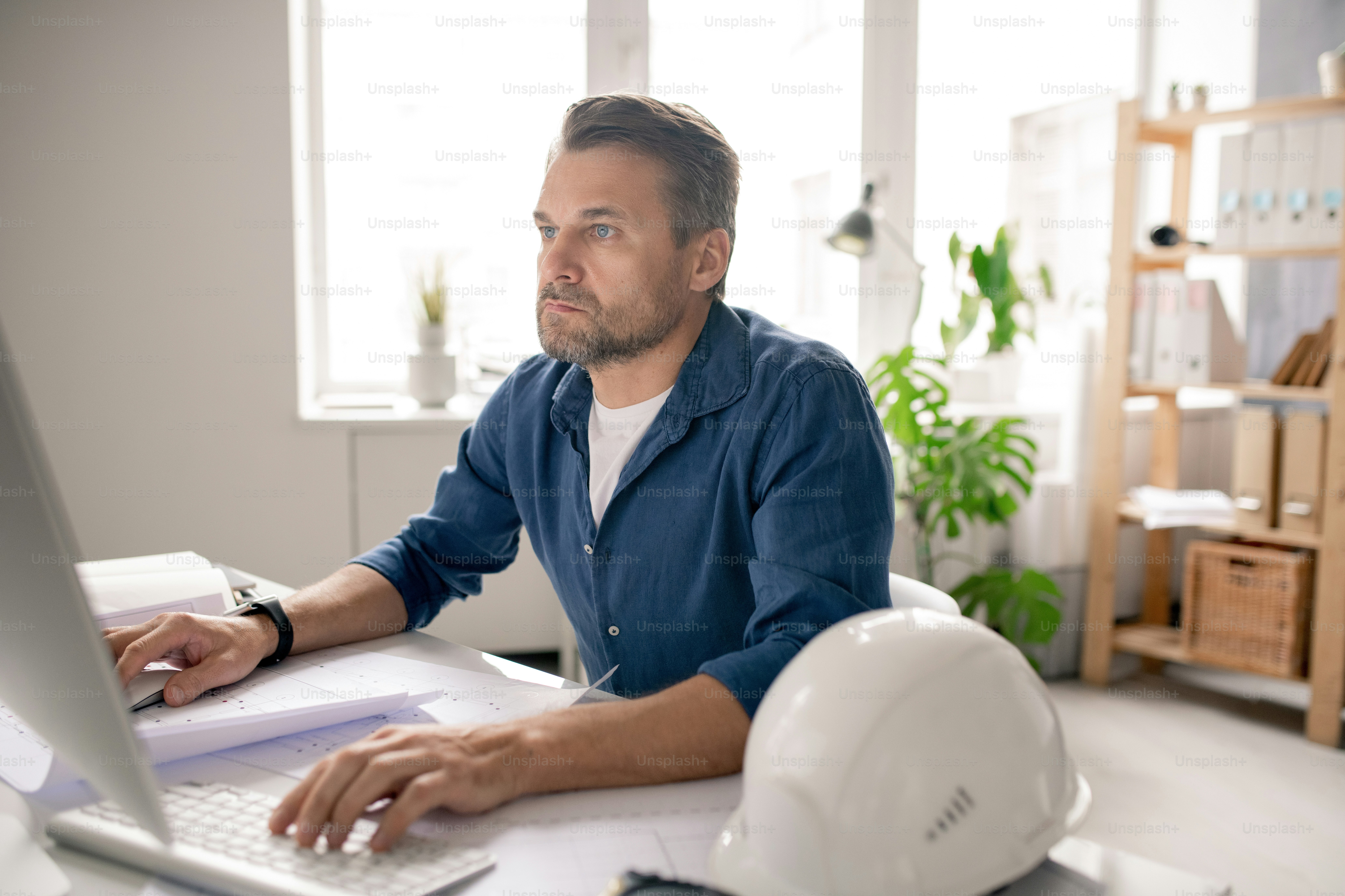 Serious engineer concentrating on work while sitting in front of ...