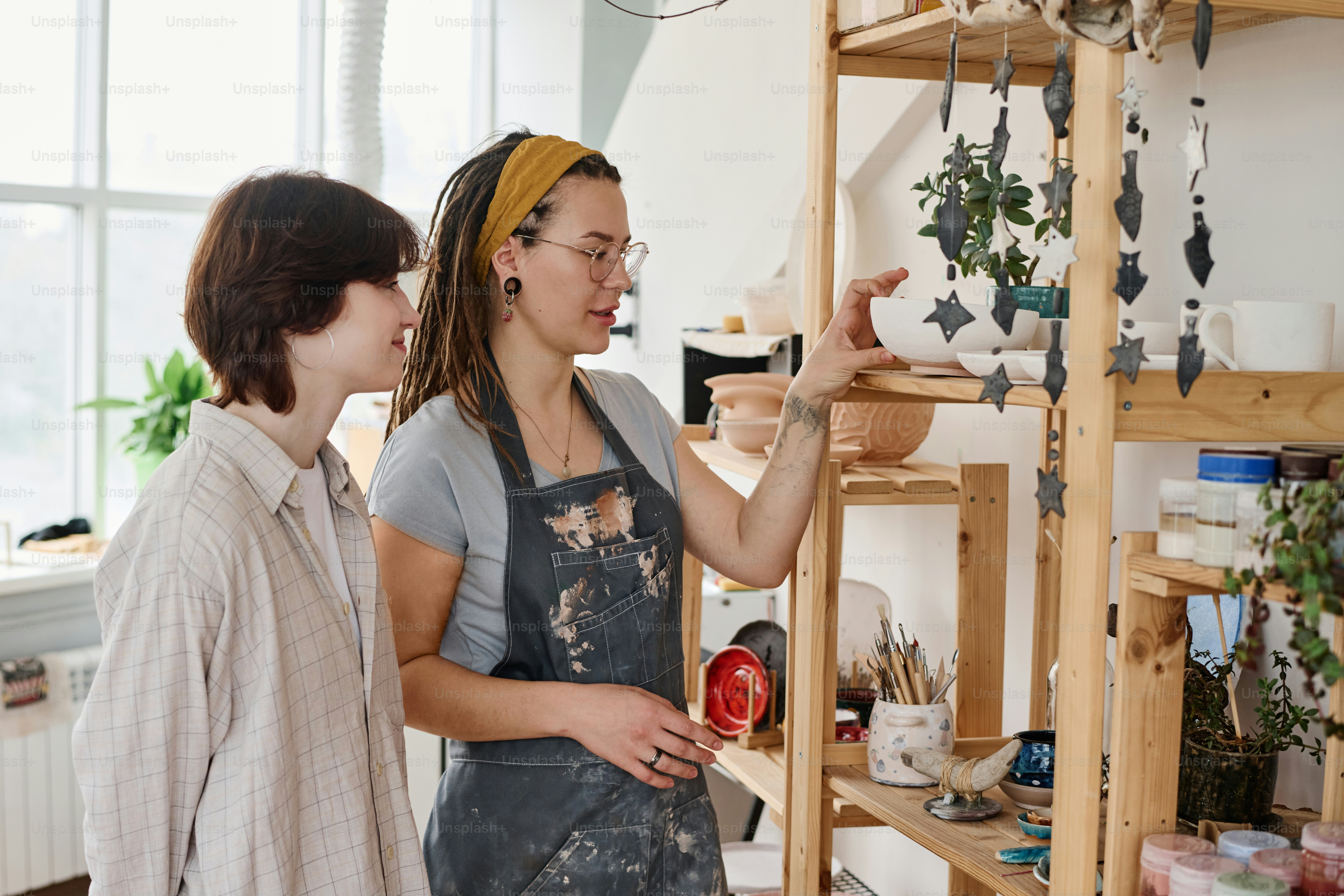 Joven empleada de una pequeña tienda de loza que muestra nuevos ...