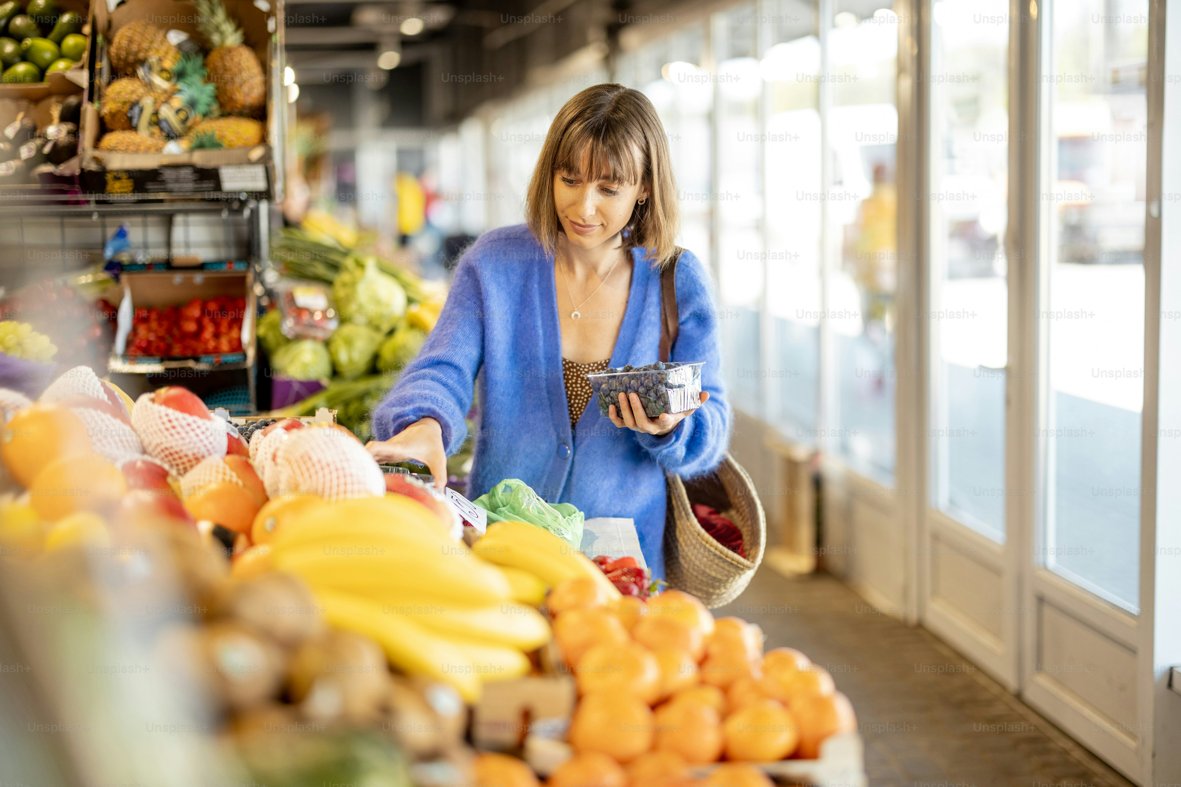 Young woman buying greens at local market, shopping fresh local raw ...
