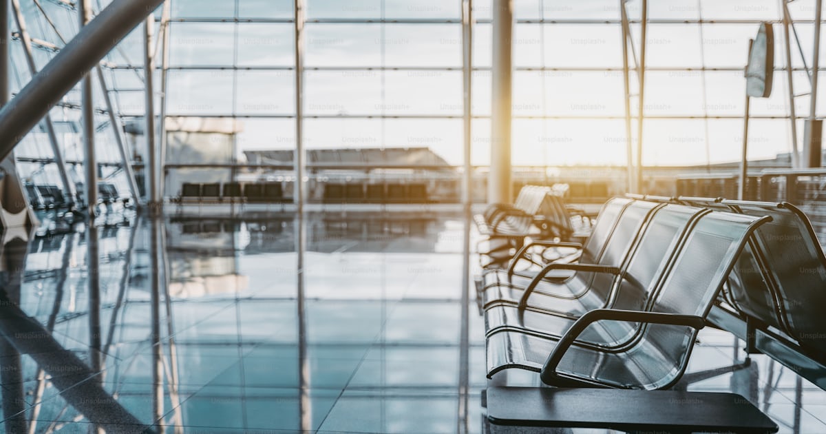 공항 또는 기차역 창고의 현대적인 밝은 인테리어에 측면에 작은 플라스틱 테이블이 있는 검은색 금속으로 만든 현대적인 좌석 열