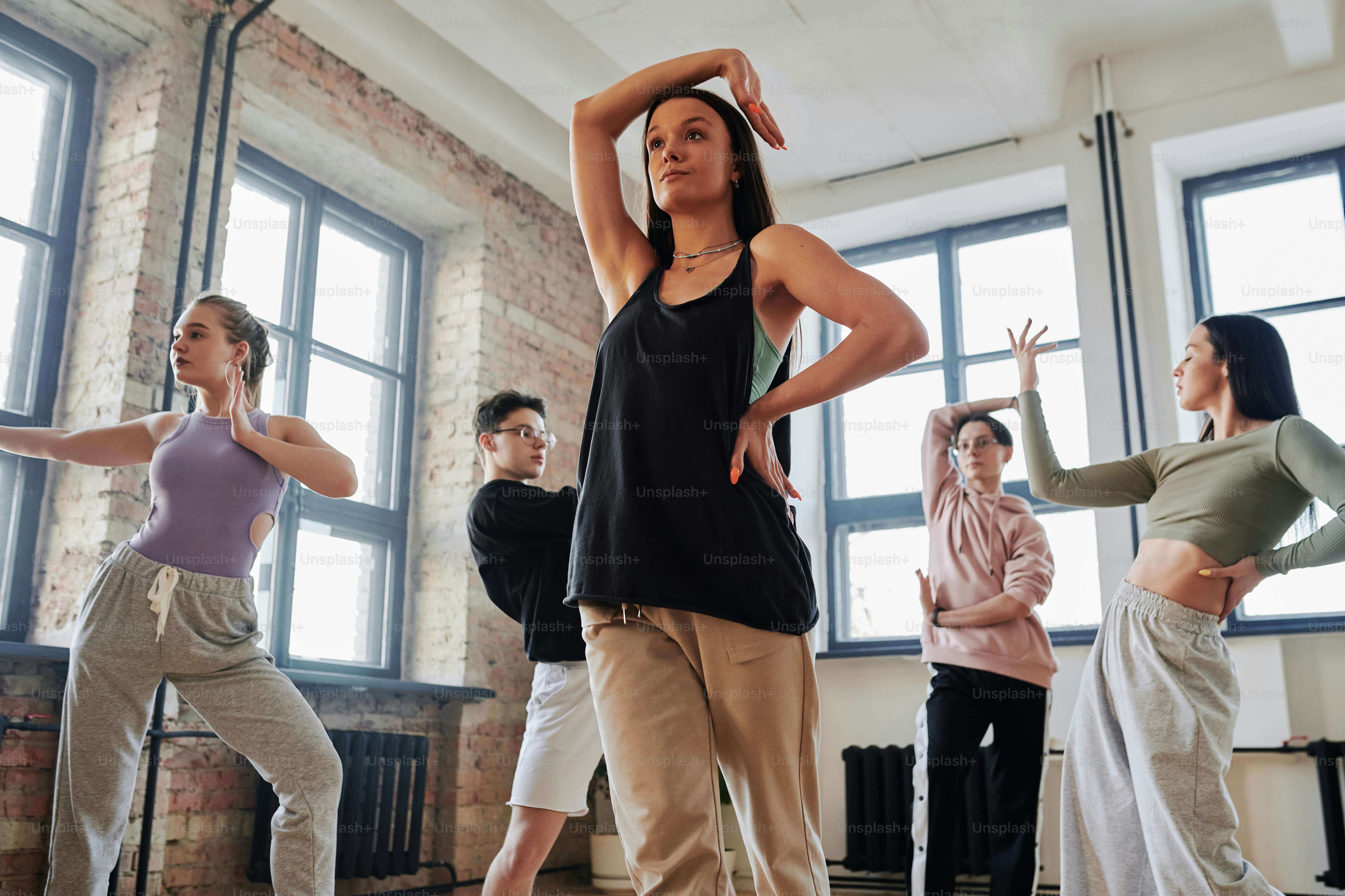Contemporary female performer in activewear keeping right arm over her ...