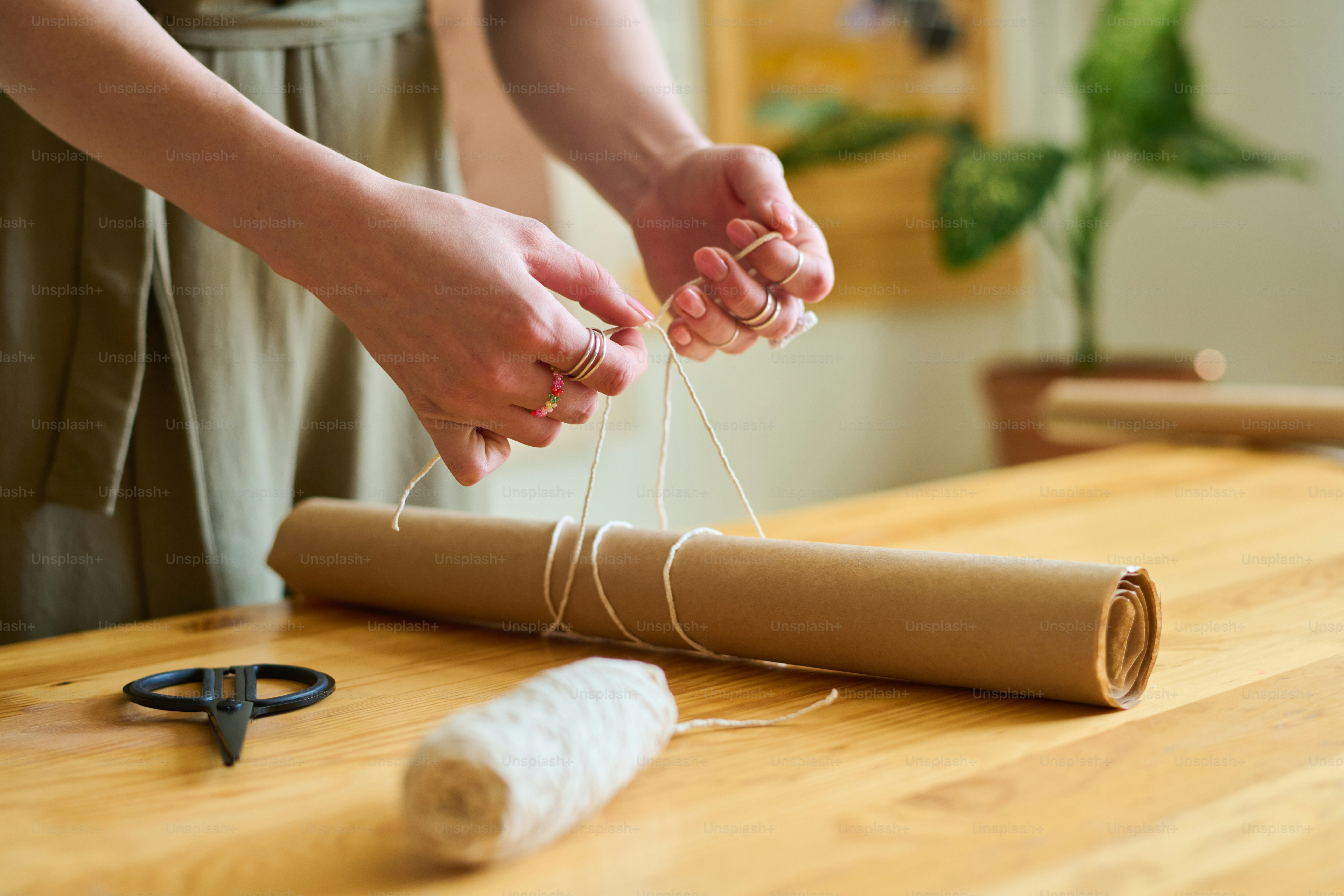 Hands of young female clerk or artisan tying white cotton thread over ...