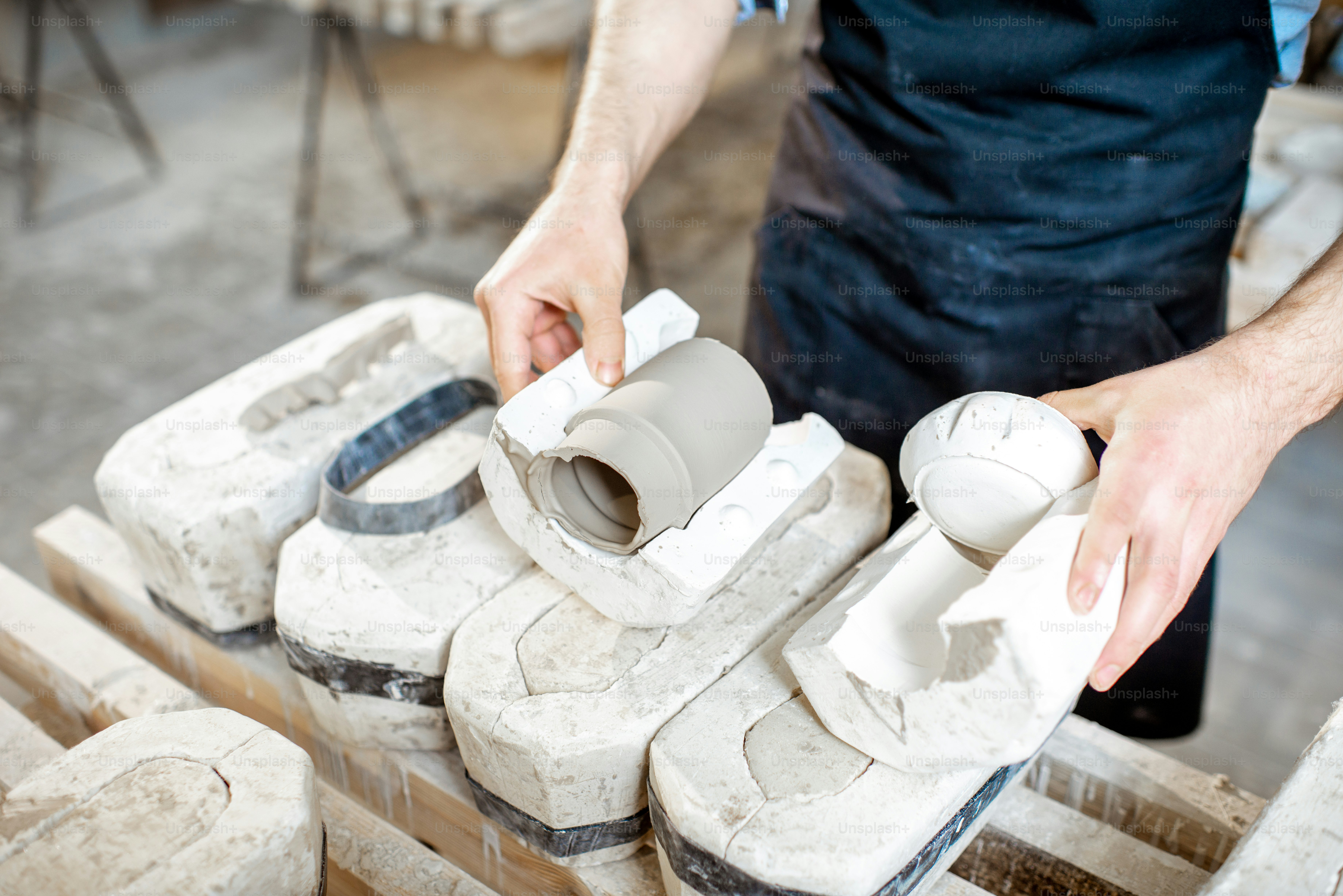 Male worker getting clay products from the gypsum forms at the pottery ...