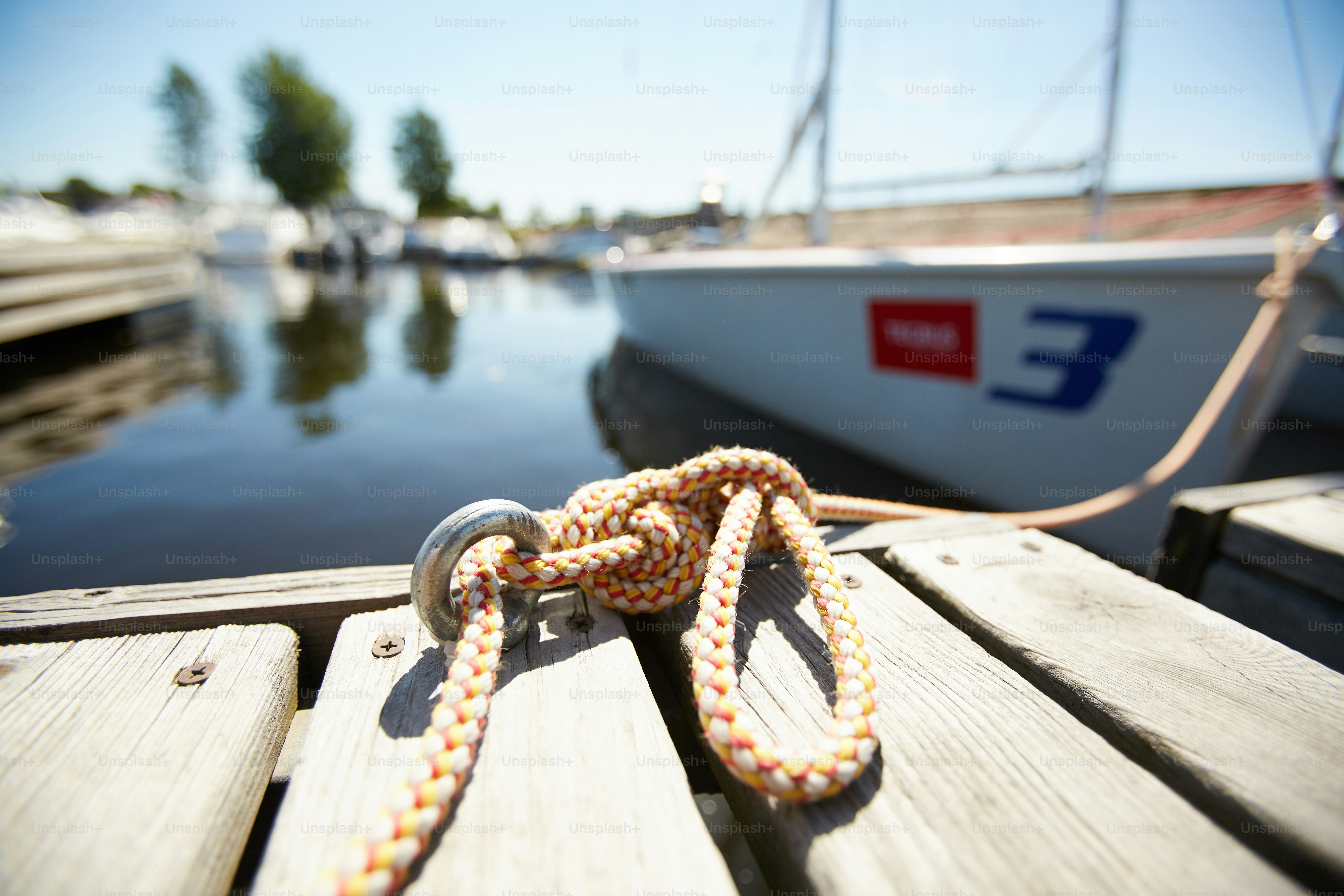 Rope tied in knot in iron loop on wooden surface of pontoon or pier ...