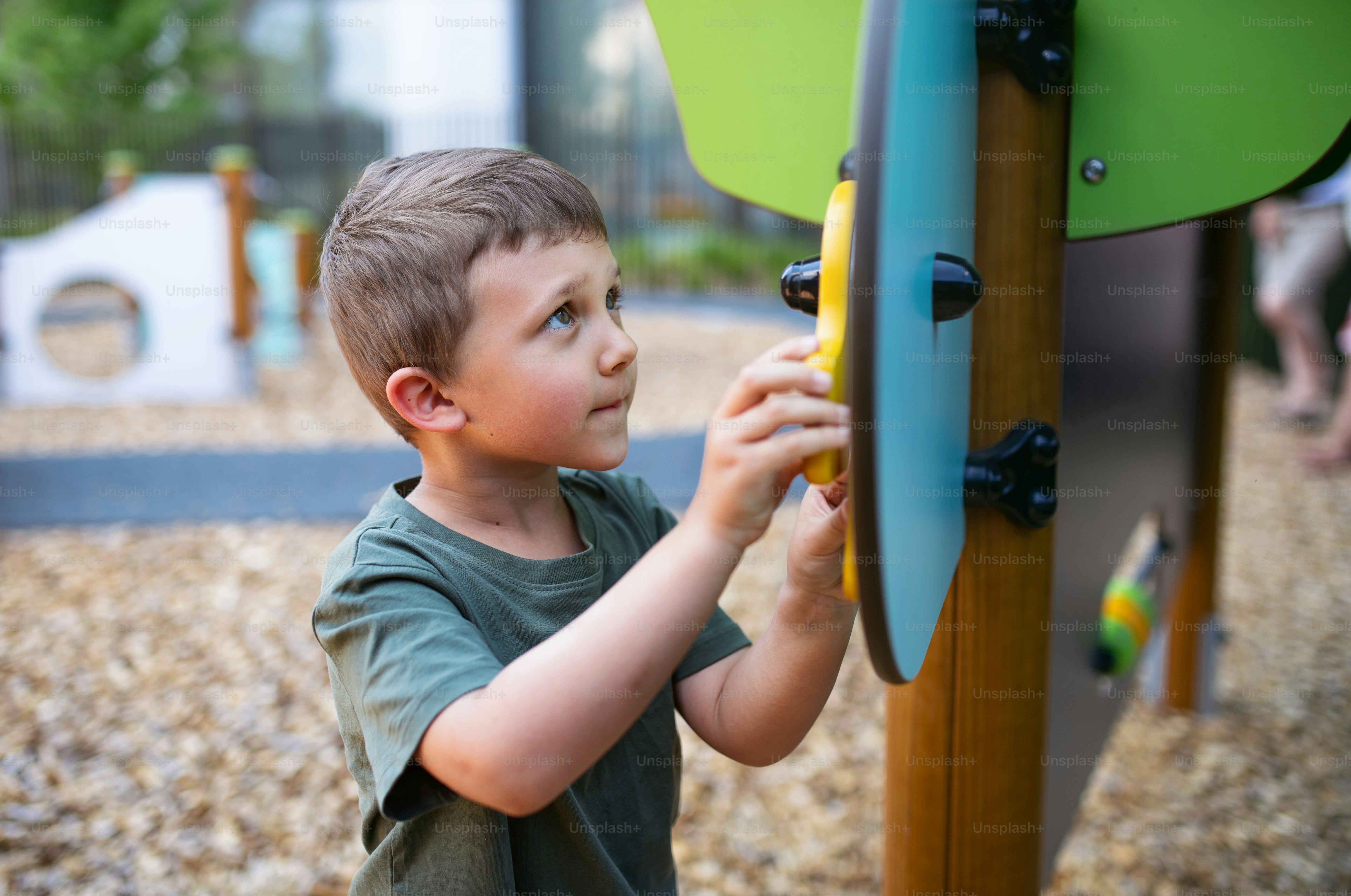 A small happy nursery school boy playing outdoors on playground. photo ...
