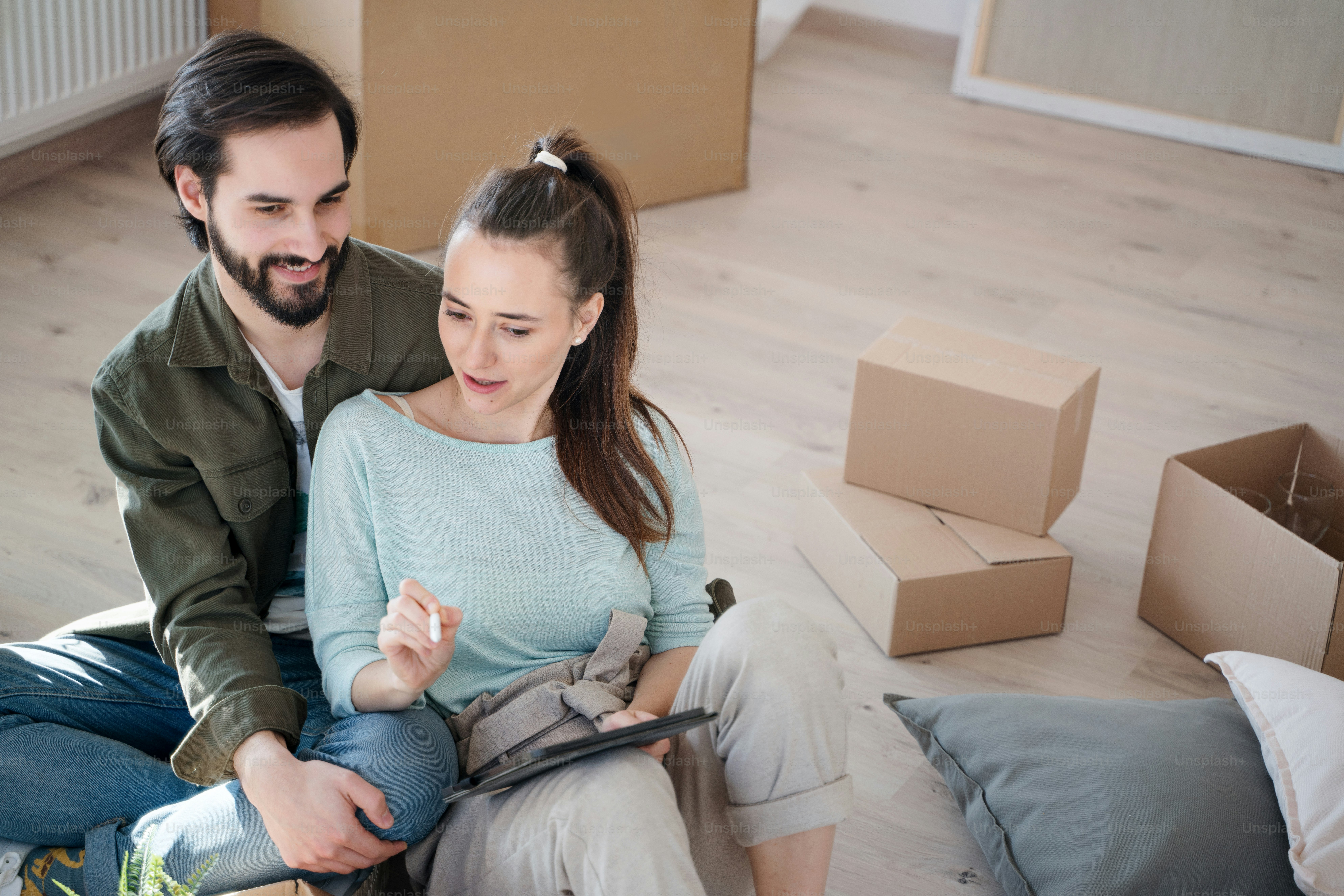 A young couple with tablet planning when moving in new flat, new home and relocation concept ...