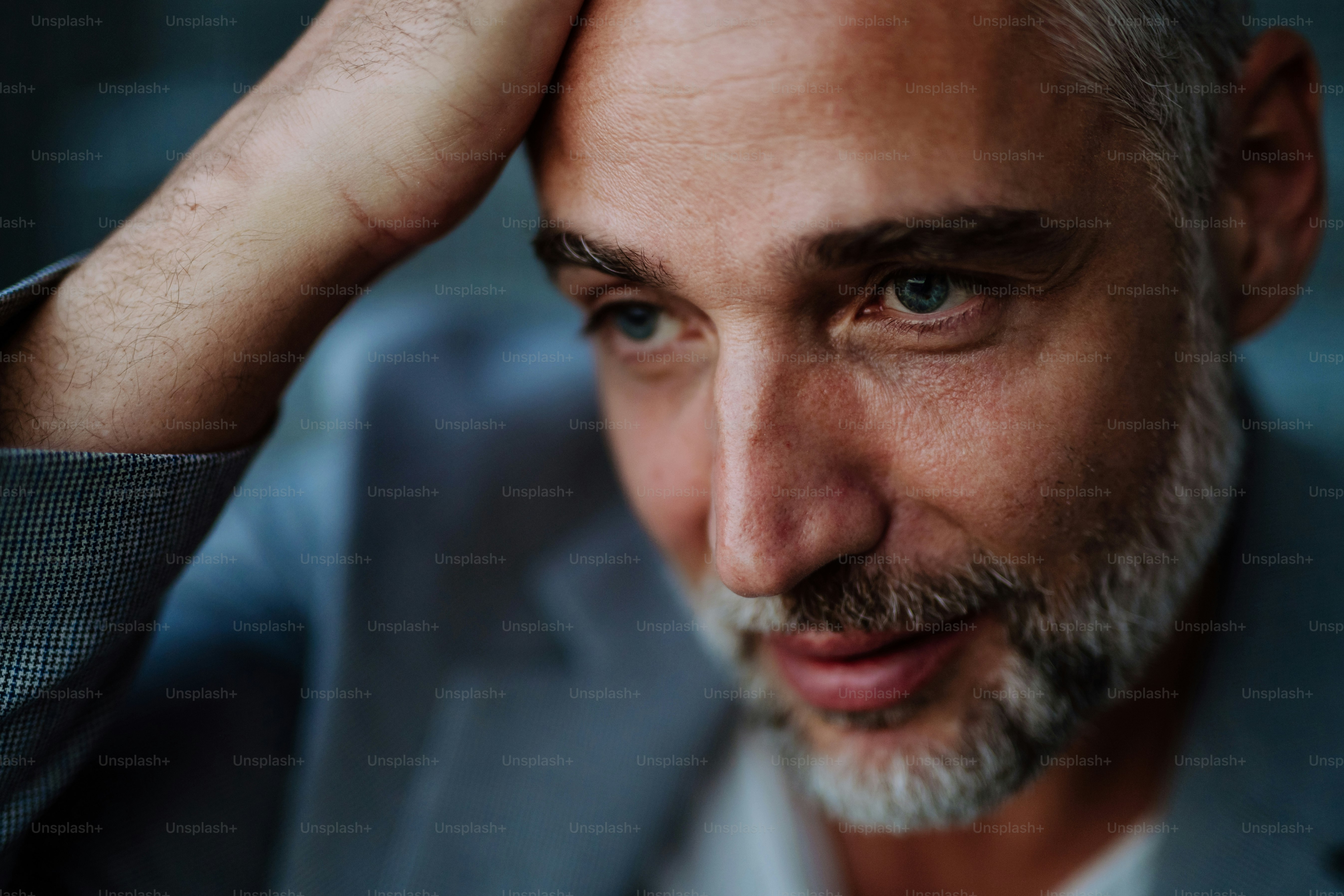A close-up portrait of handsome businessman touching his head looking ...