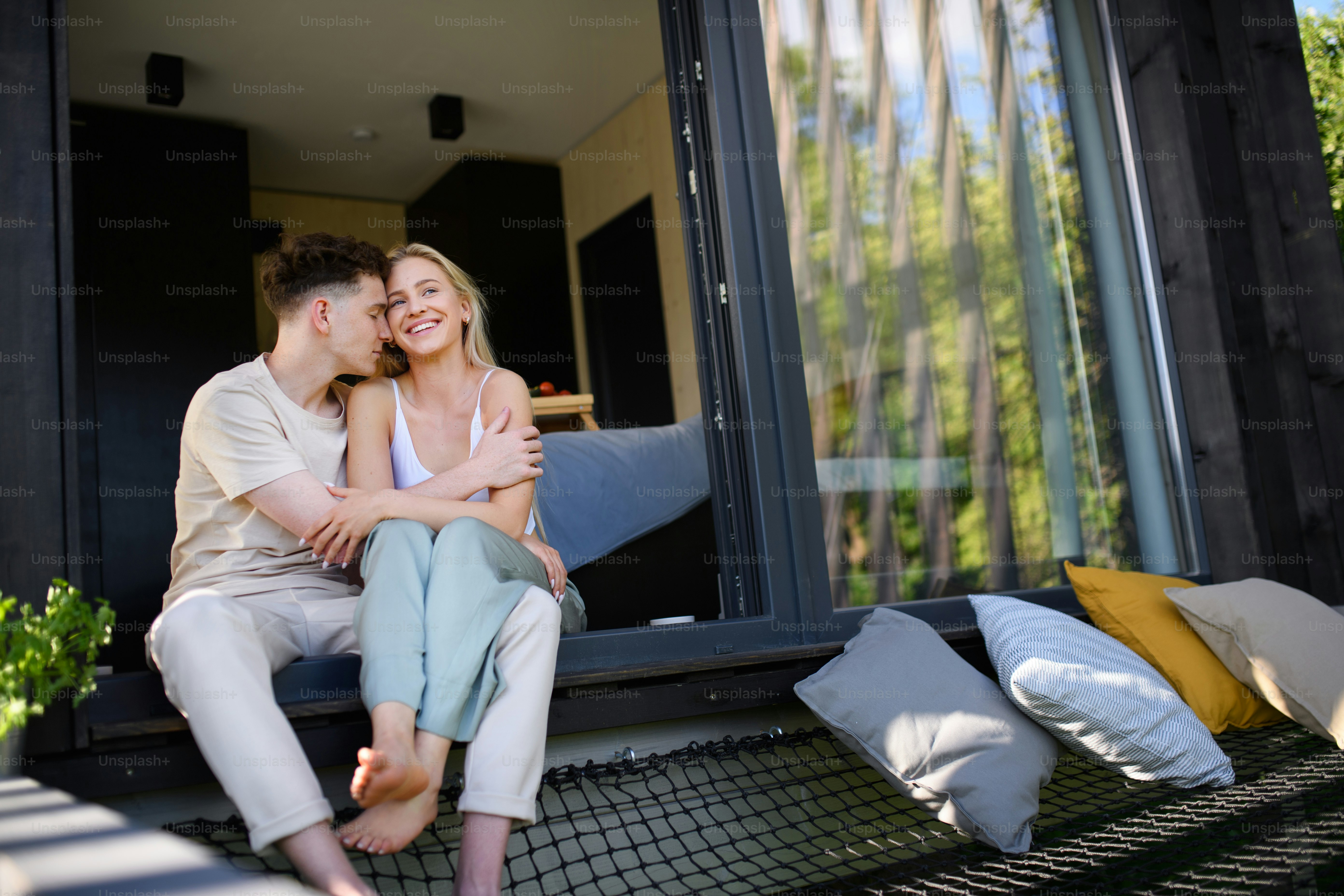 A young couple sitting and cuddling in hammock terrace in their new ...