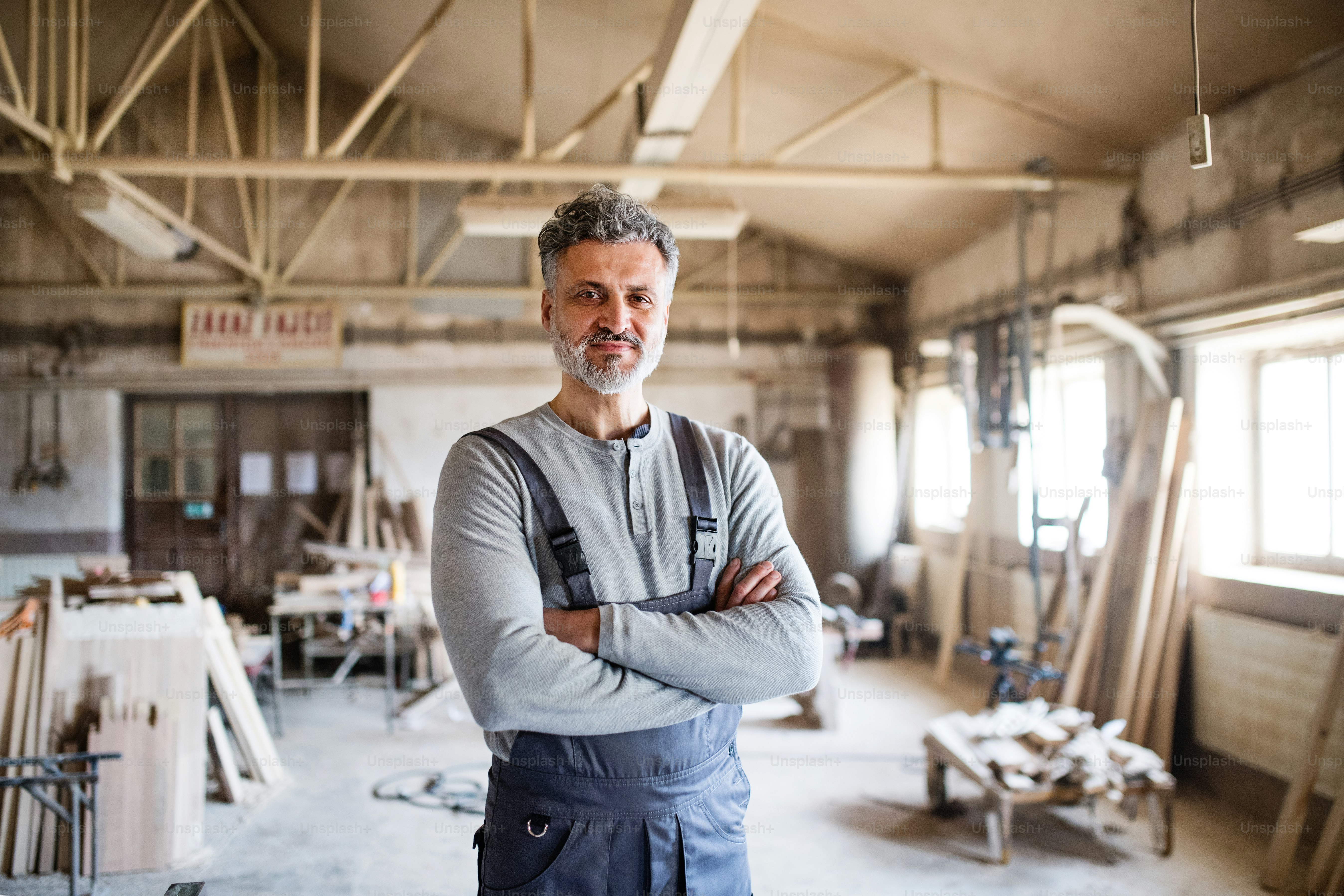 Portrait of a mature man worker in the carpentry workshop, arms crossed ...