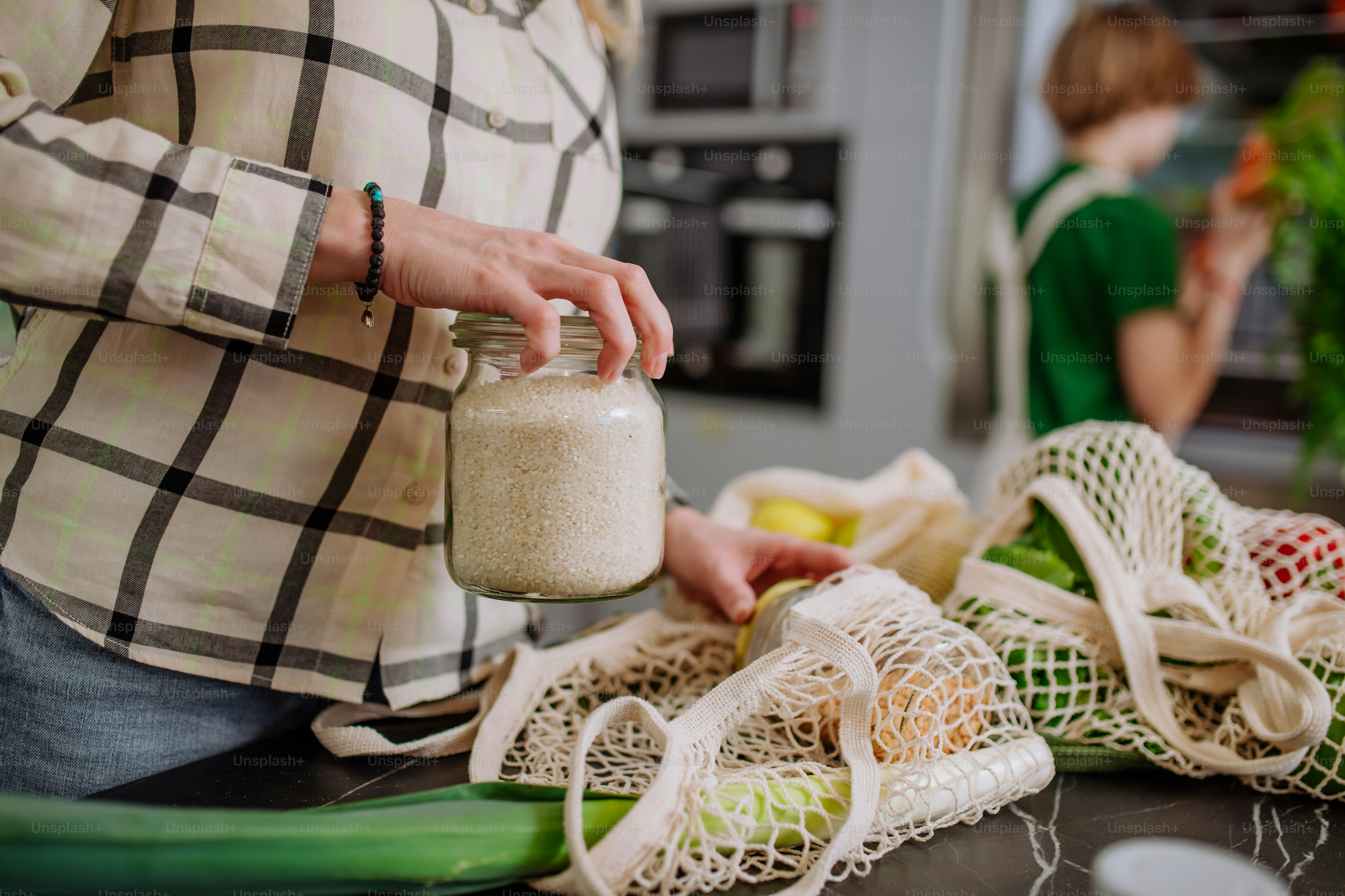 A mother unpacking local food in zero waste packaging from bag with ...