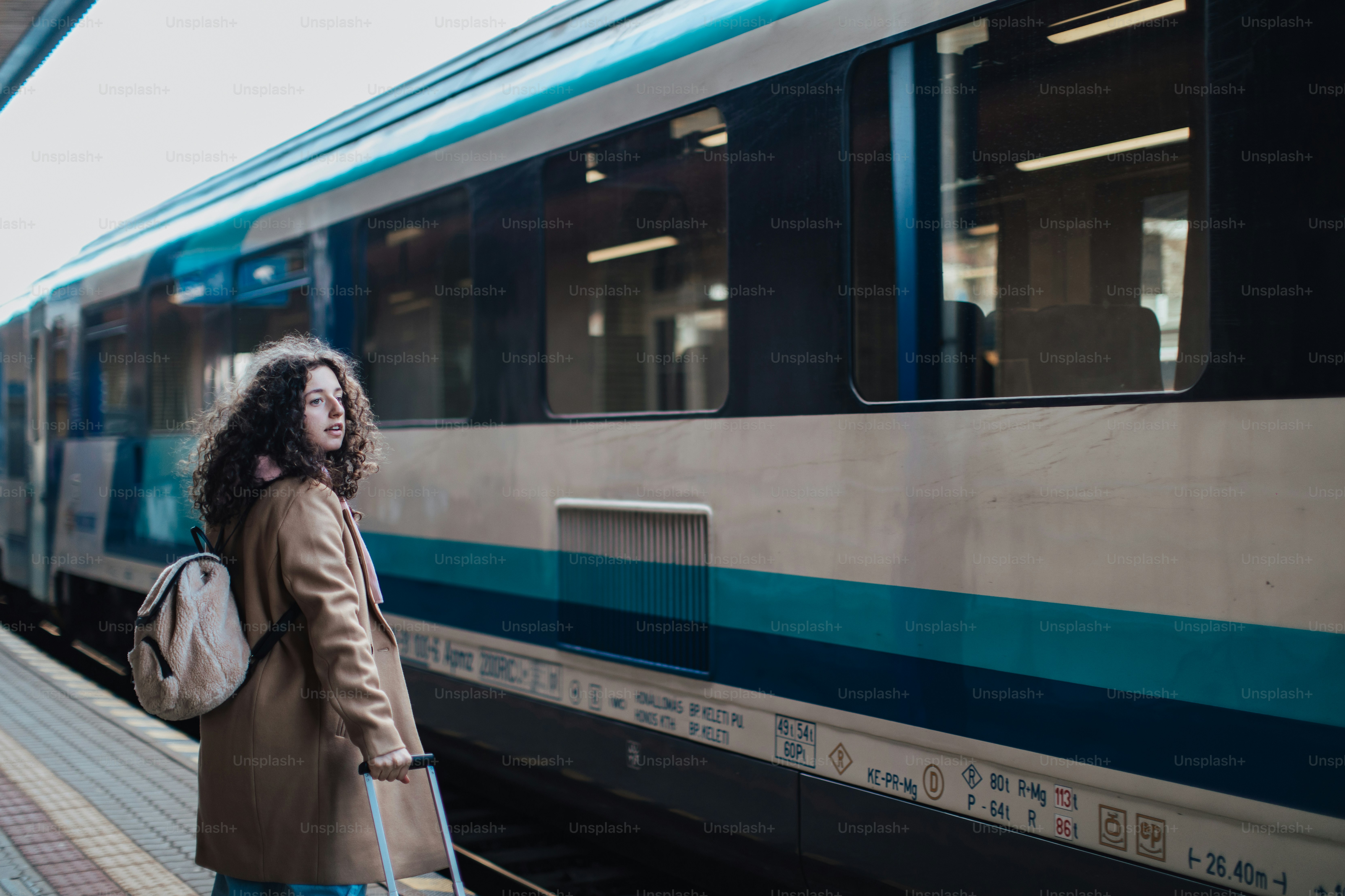 A happy young traveler woman with luggage getting off the train at ...