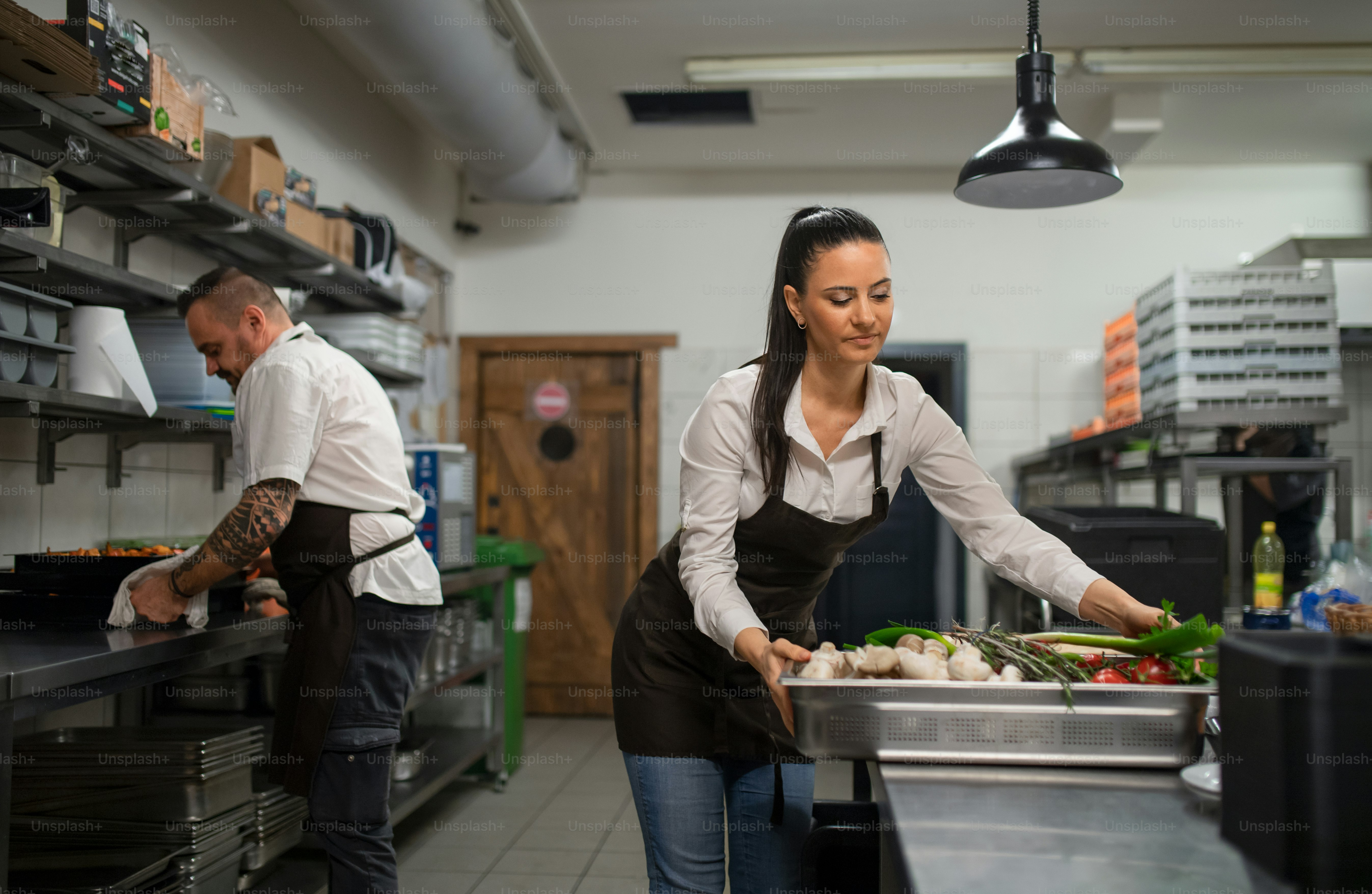 A chef and cook working on their dishes indoors in restaurant kitchen ...