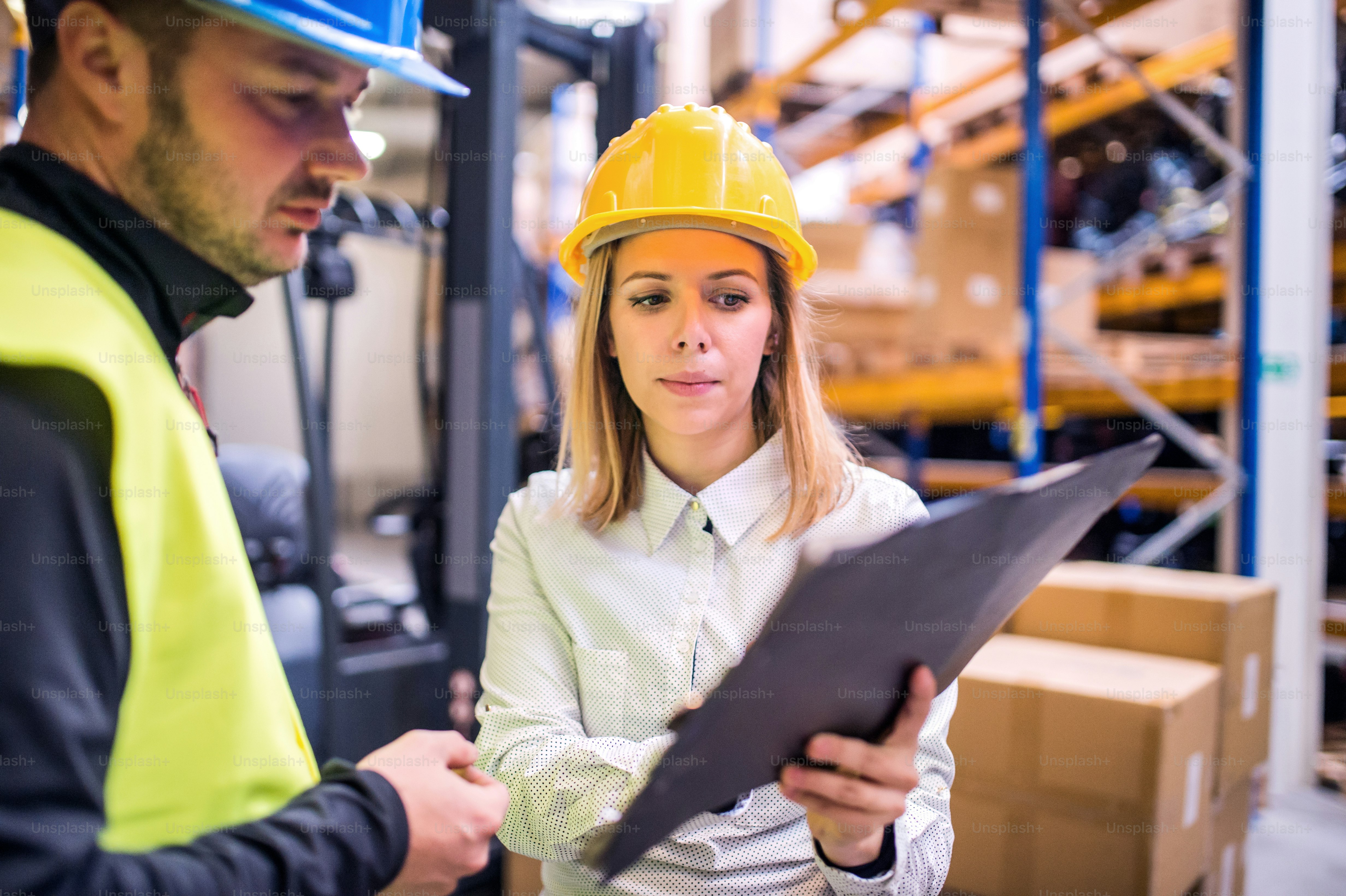 Young workers working together. Man forklift driver and a woman in a ...