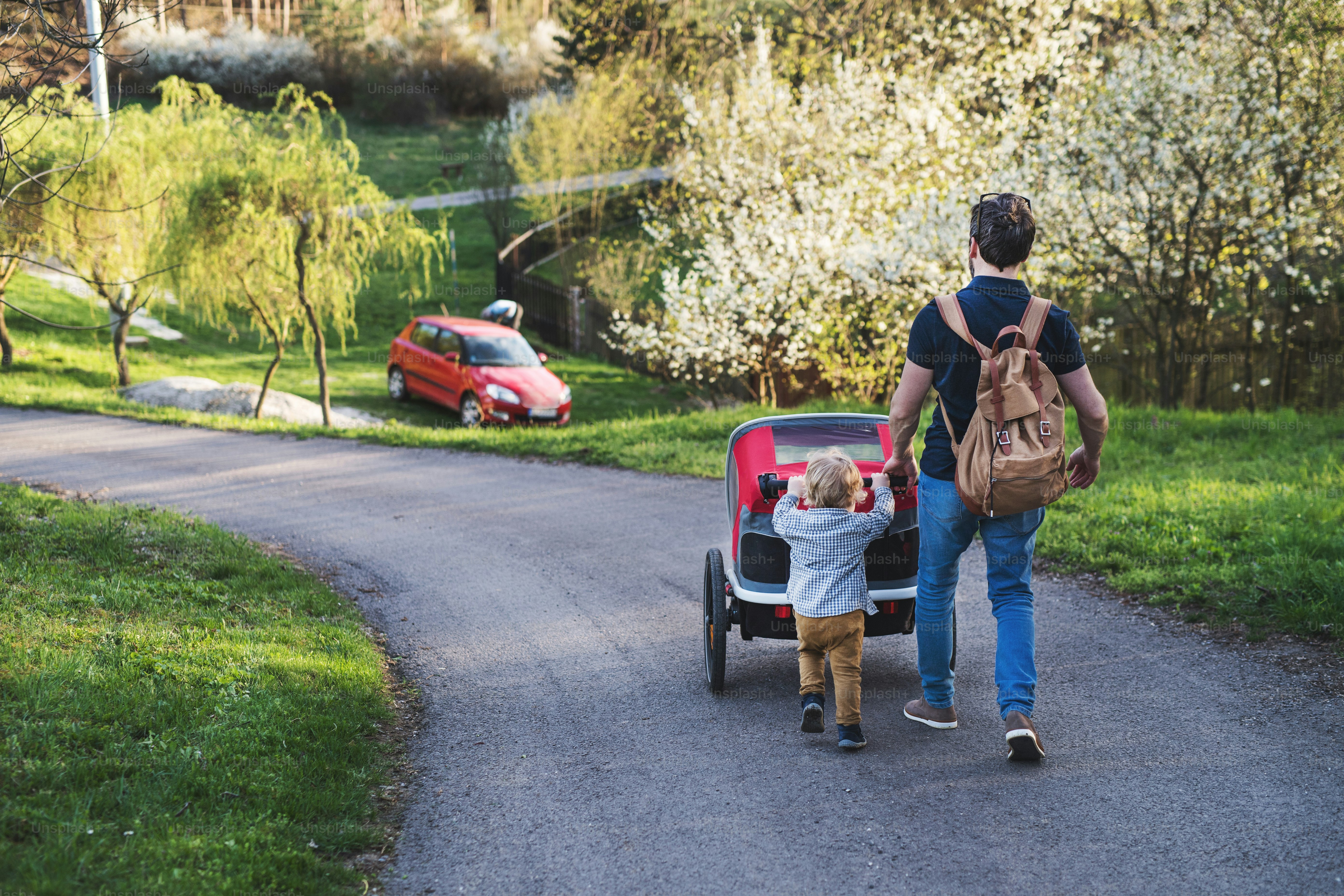 A father with two toddler children sitting in jogging stroller on a ...