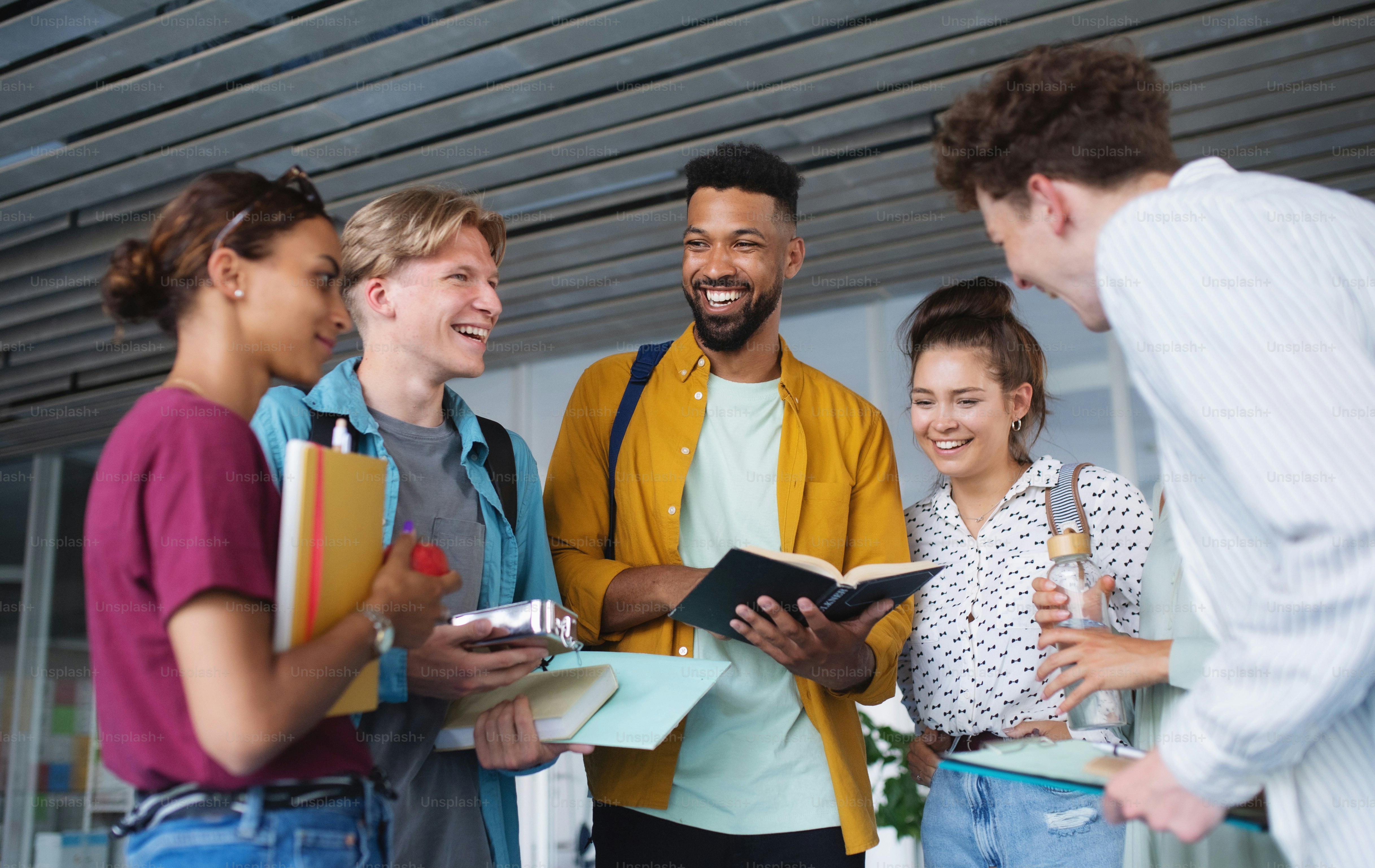 Group of cheerful university students standing in corridor indoors ...