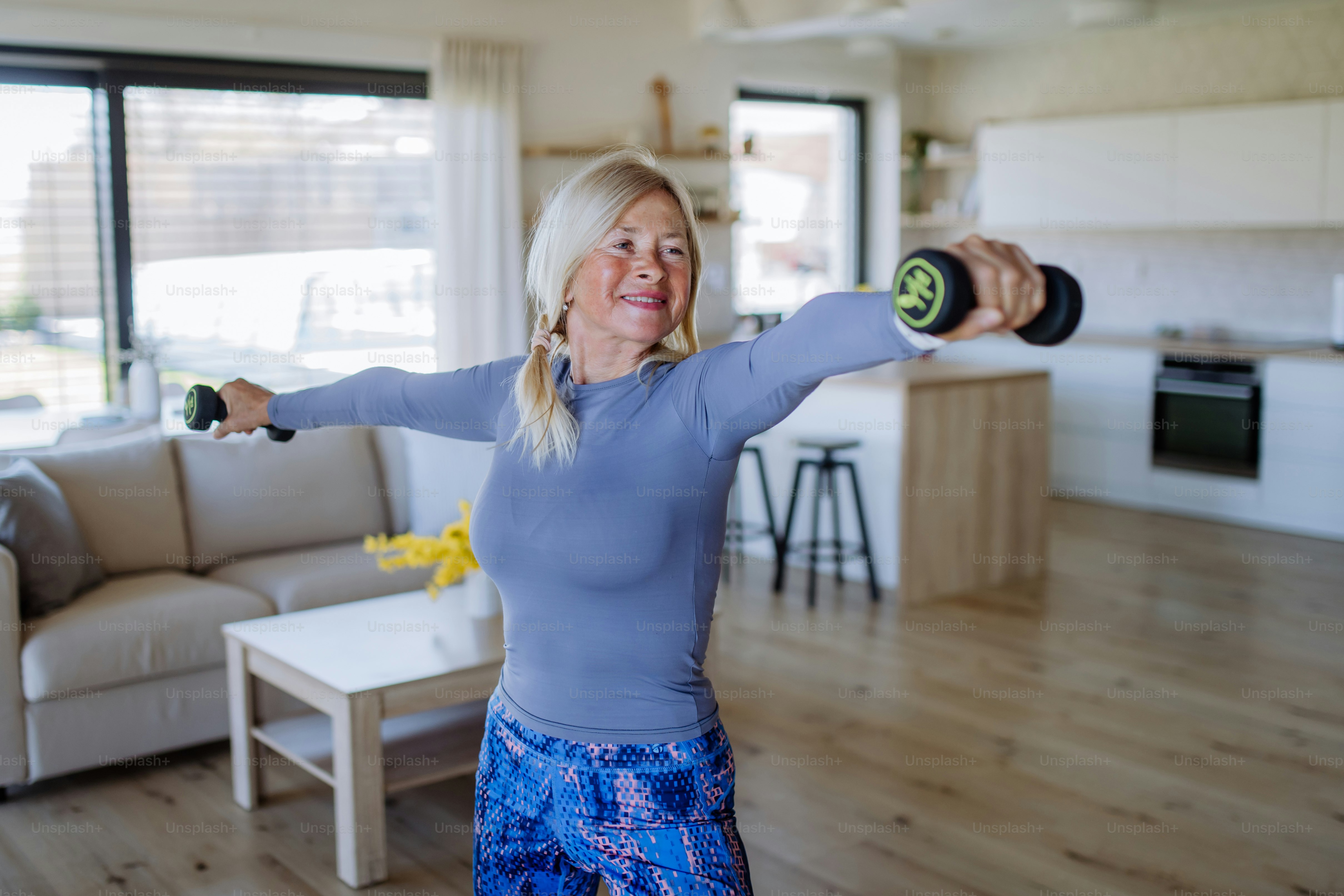 A fit senior woman exercising with dumbbells at home, active lifestyle ...