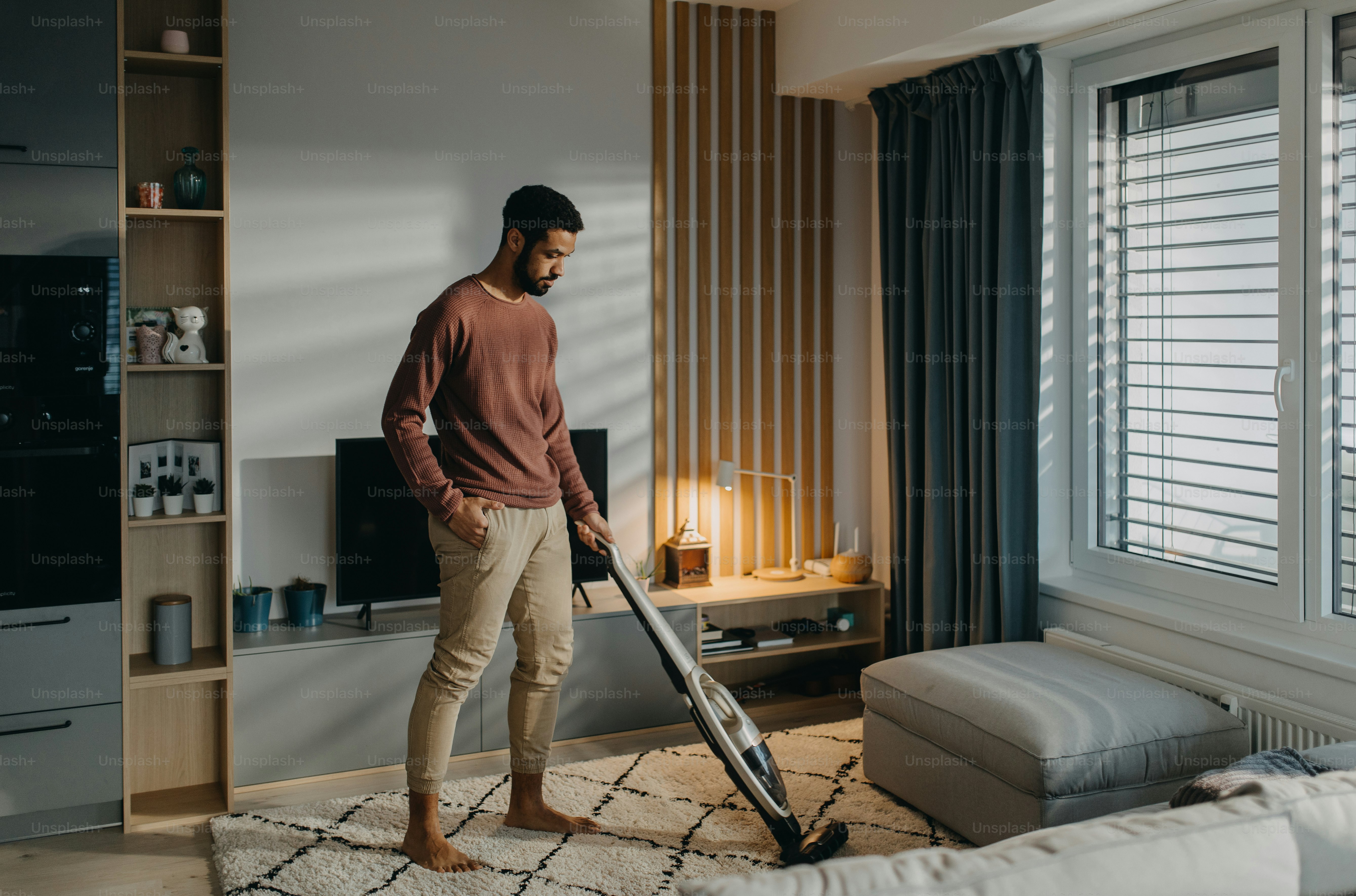 A young man hoovering carpet with vacuum cleaner in living room photo ...