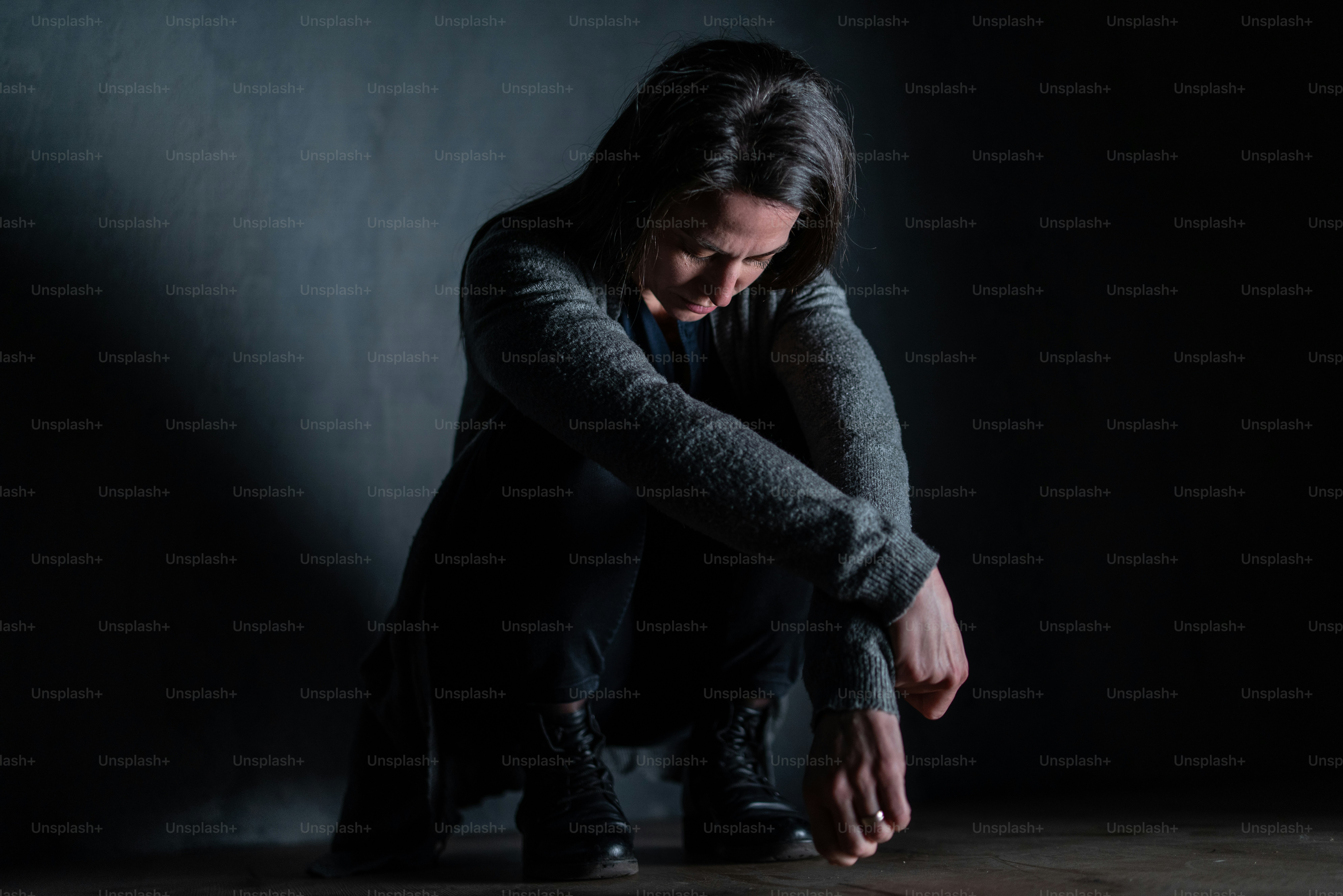 A sad mid-adult woman, alone in darkness, sitting and thinking. photo ...