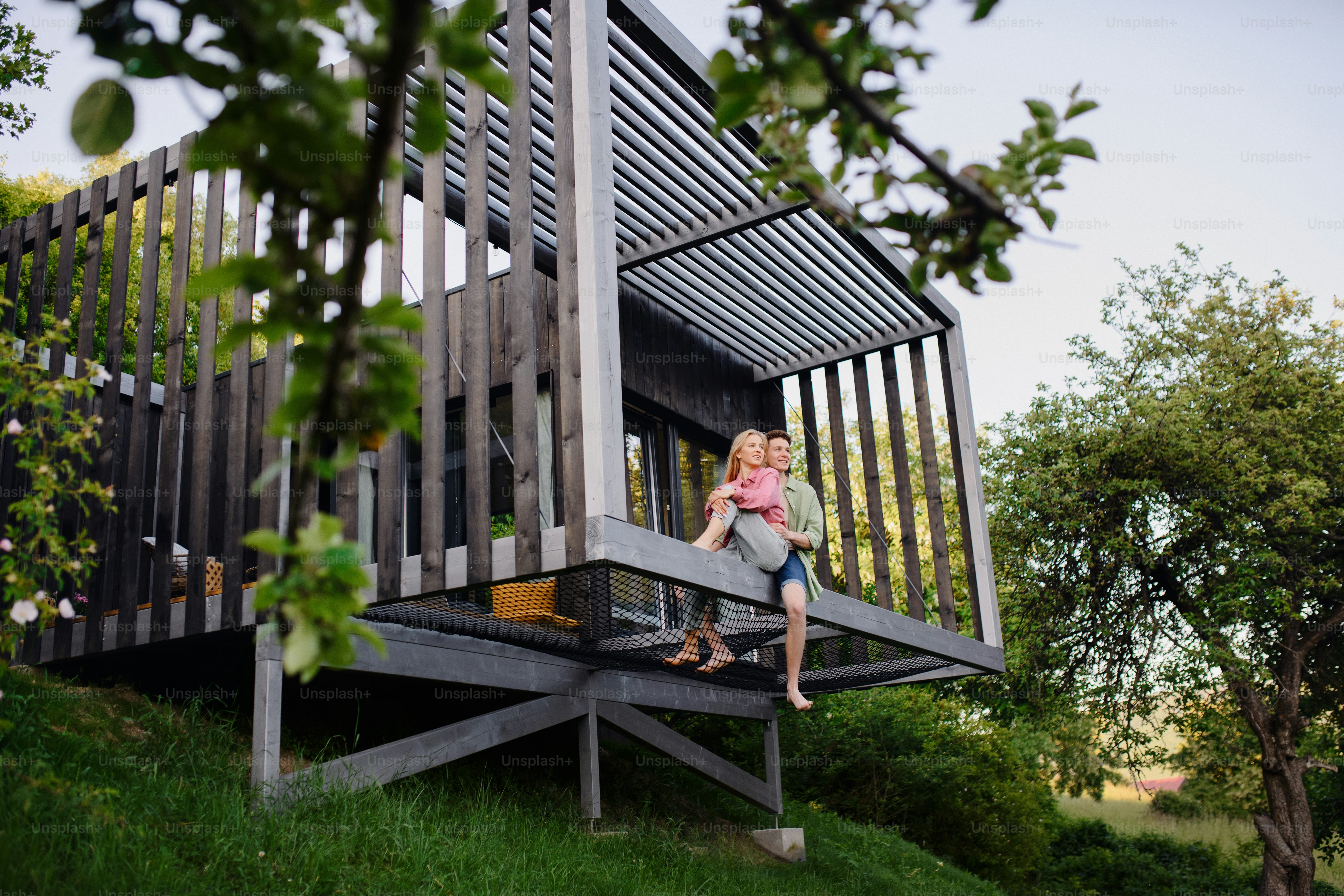 A young couple sitting and cuddling in hammock terrace in their new ...