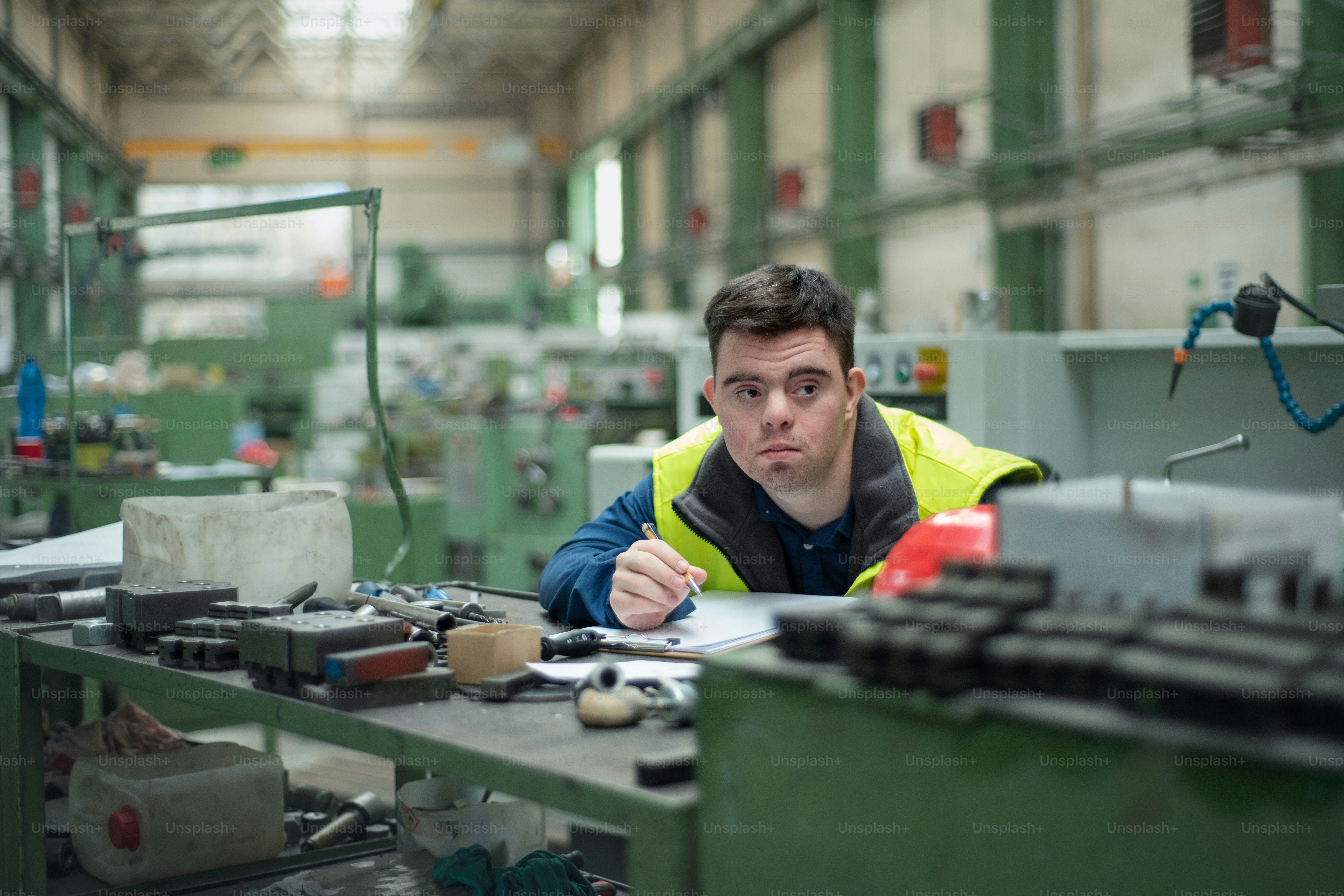 A young man with Down syndrome working in industrial factory, social ...