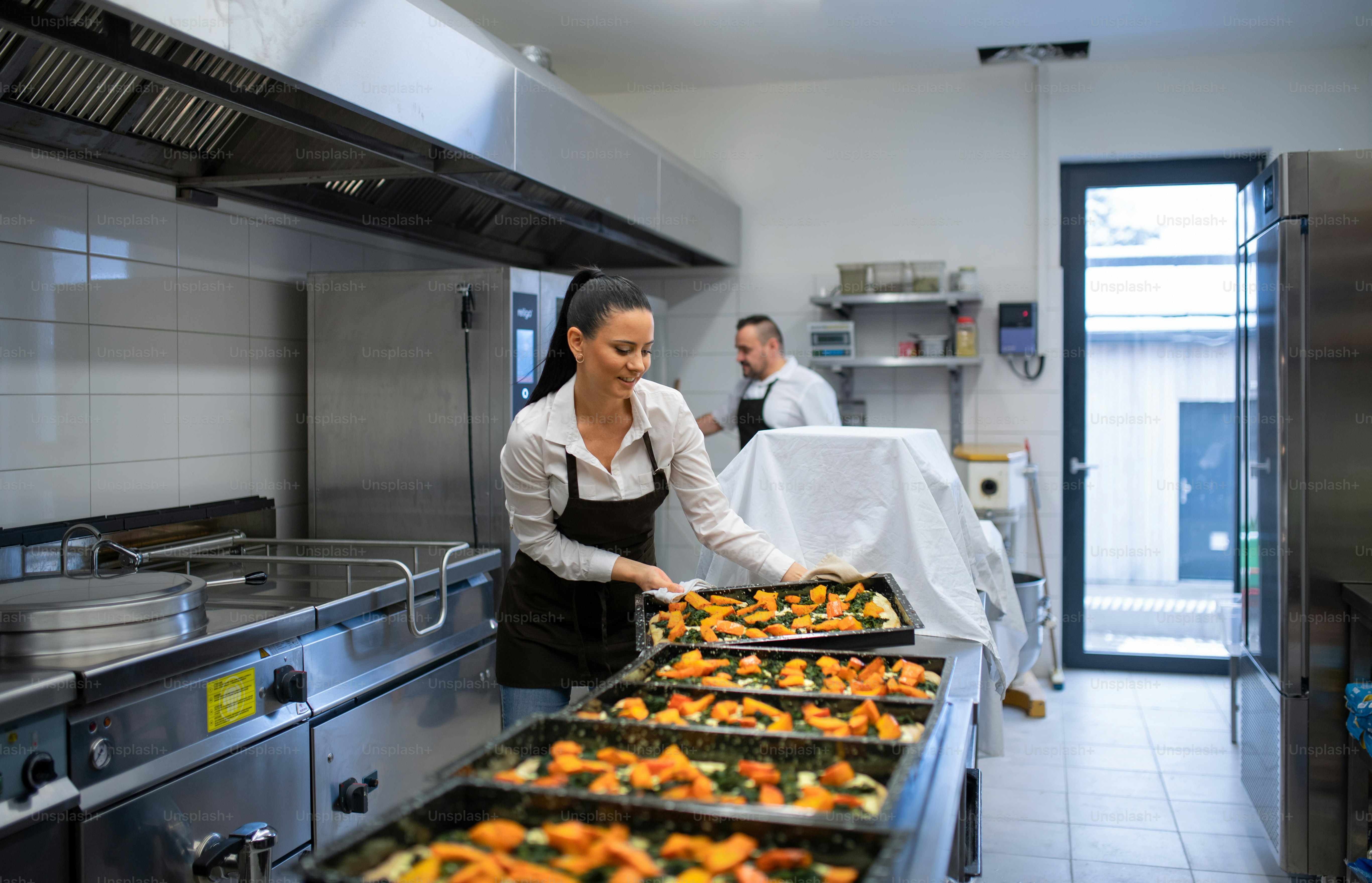 A chef and cook working on their dishes indoors in restaurant kitchen ...