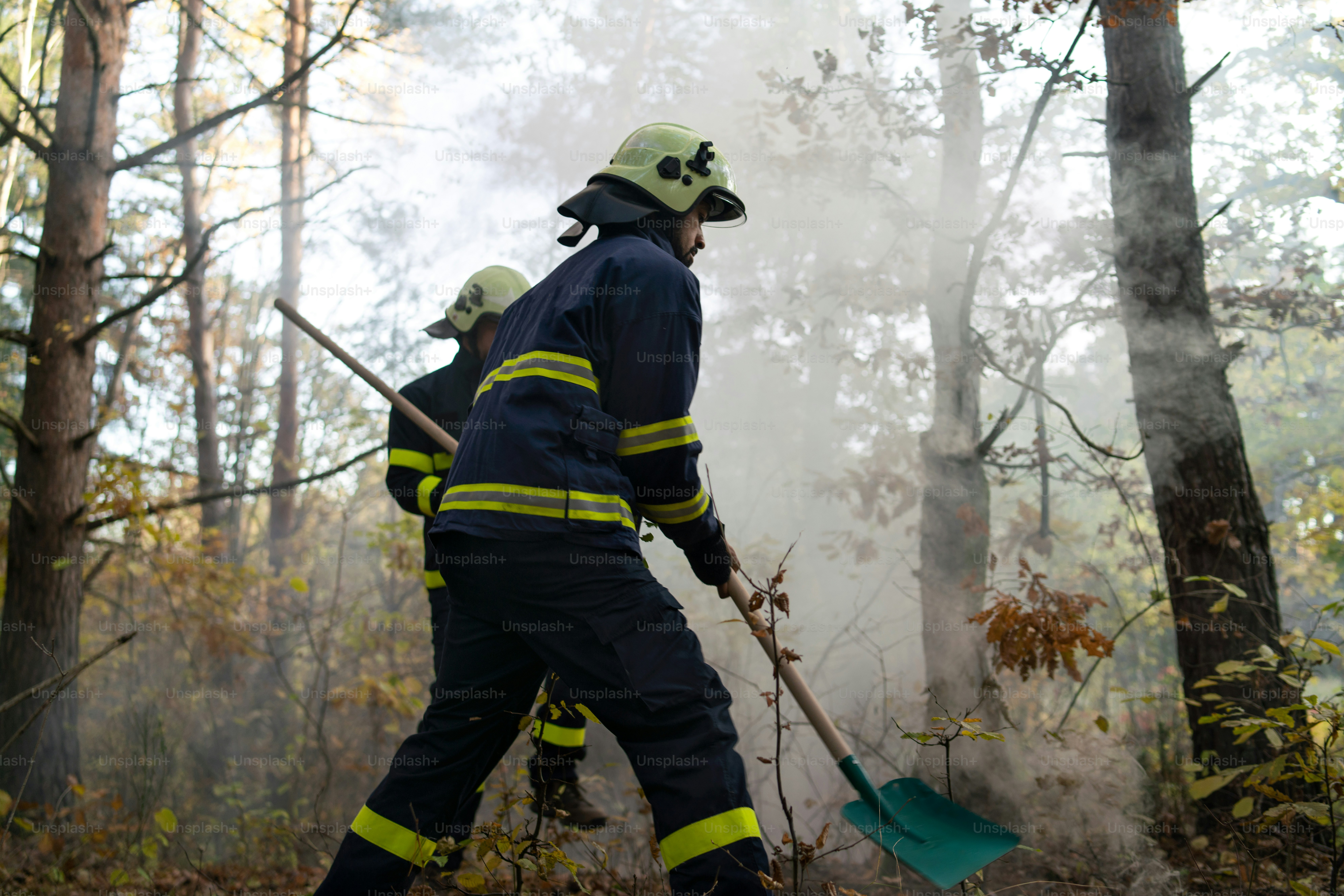 Firefighters men at action, running through the smoke with shovels to ...
