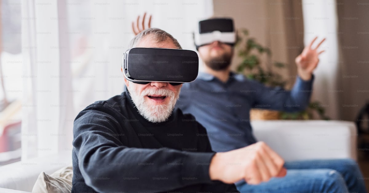 ヒップスターの息子と、自宅でvrゴーグルを装着した高齢の父親。2世代が屋内で、楽しんでいます。の写真 Unsplashの家族の画像