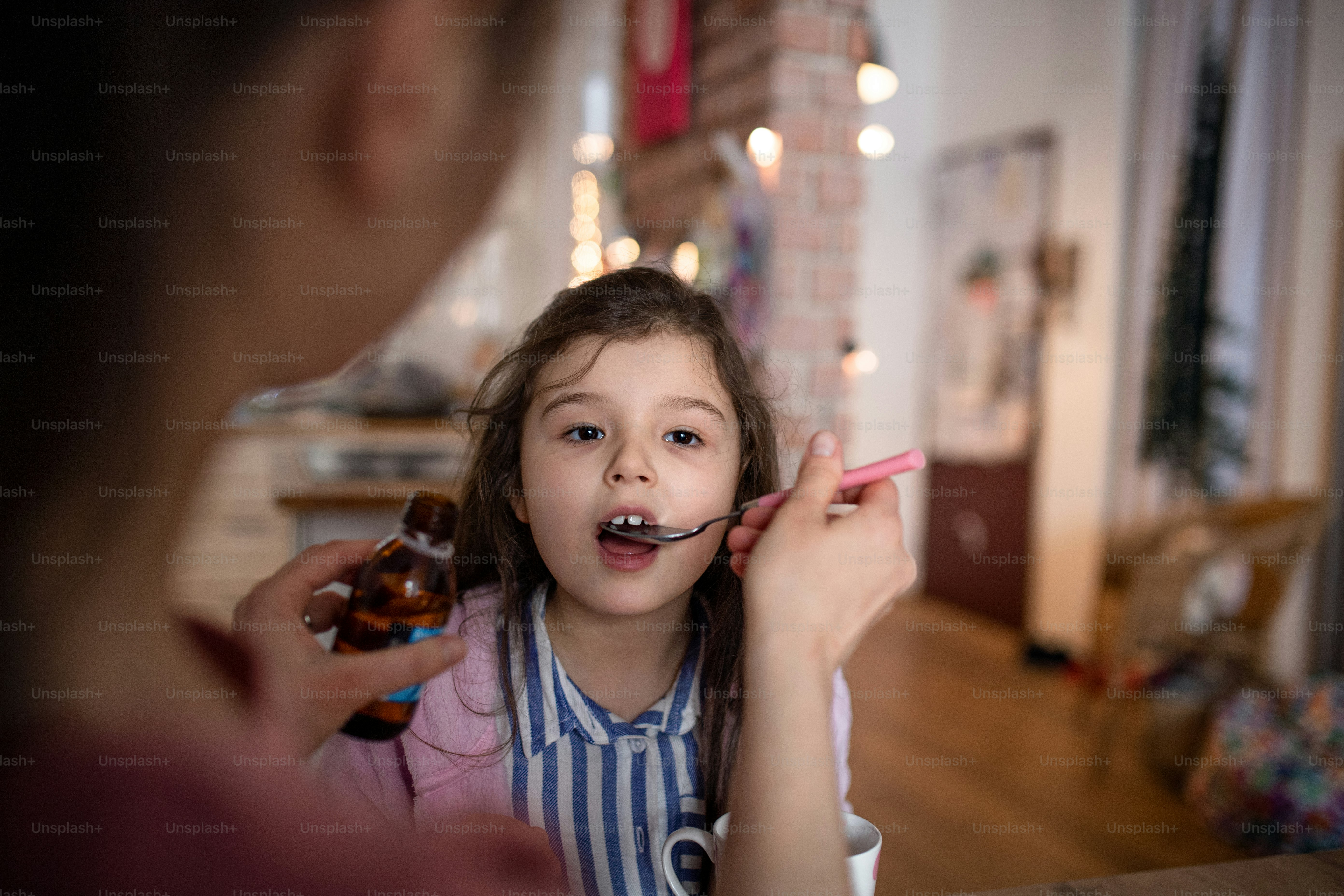 Portrait of mother looking after sick small daughter at home, giving ...