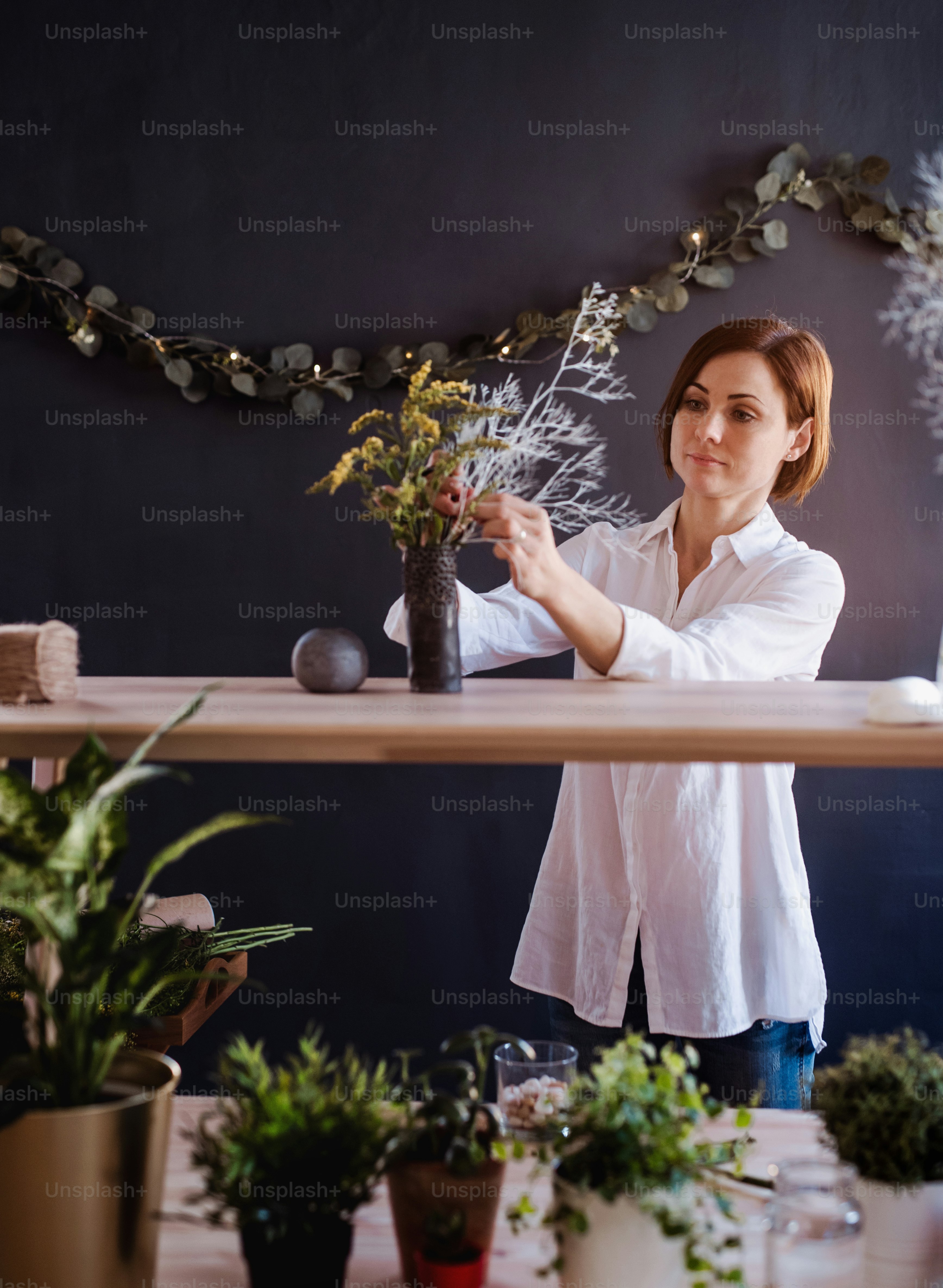 A young creative woman arranging flowers in a flower shop. A startup of ...