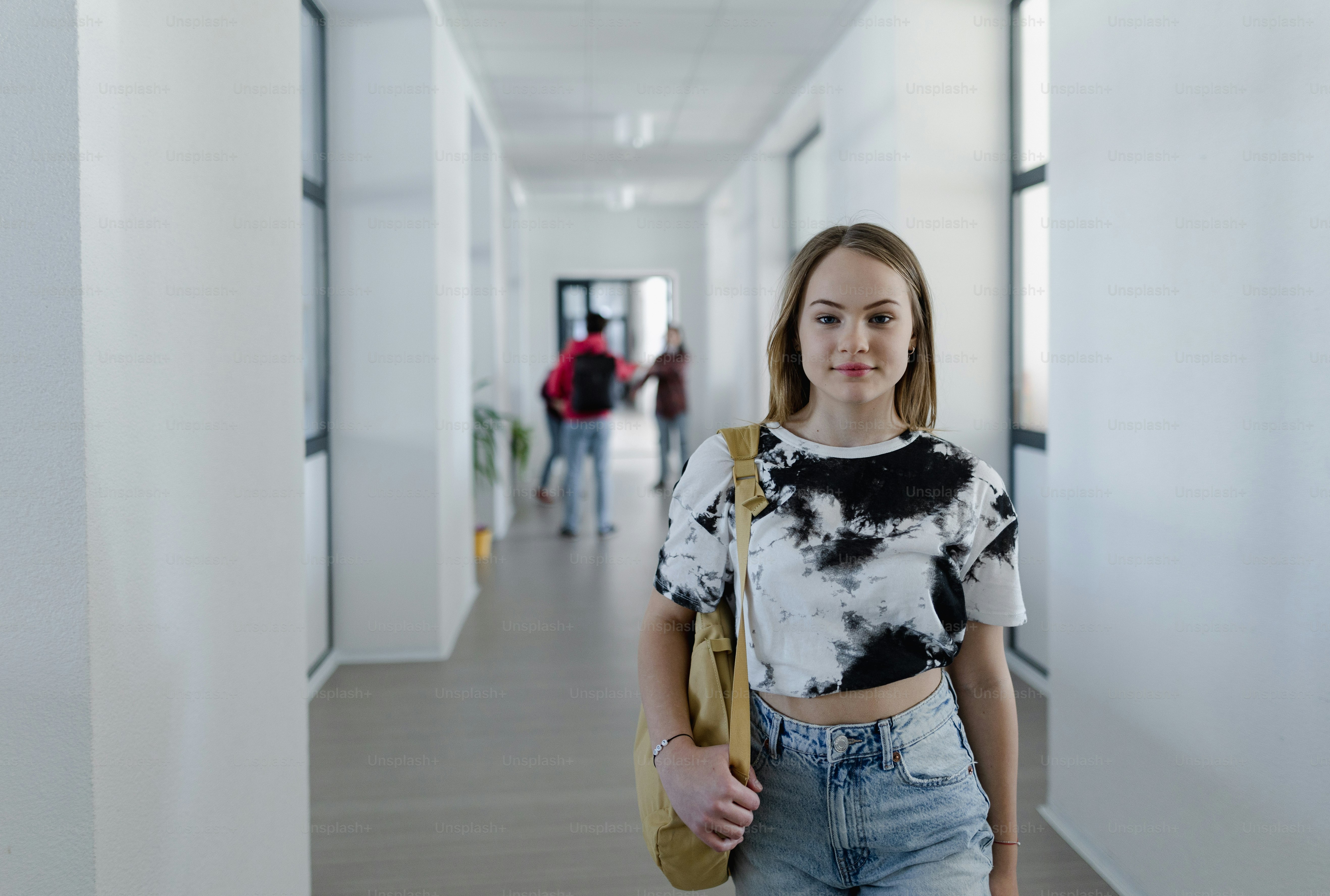 Young high school students walking in a corridor at school, back to ...