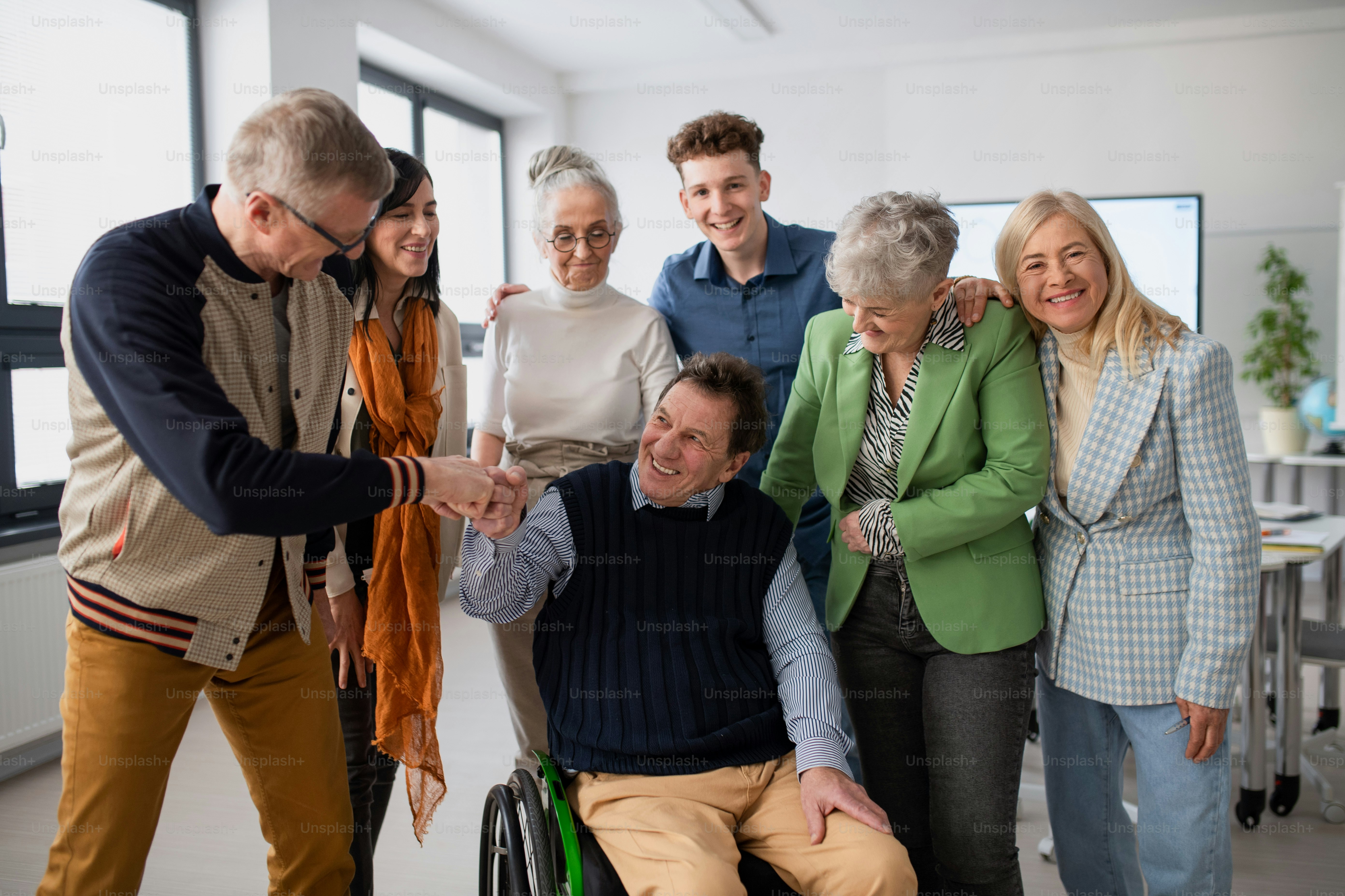Happy senior students meeting with their friend on wheelchair at ...