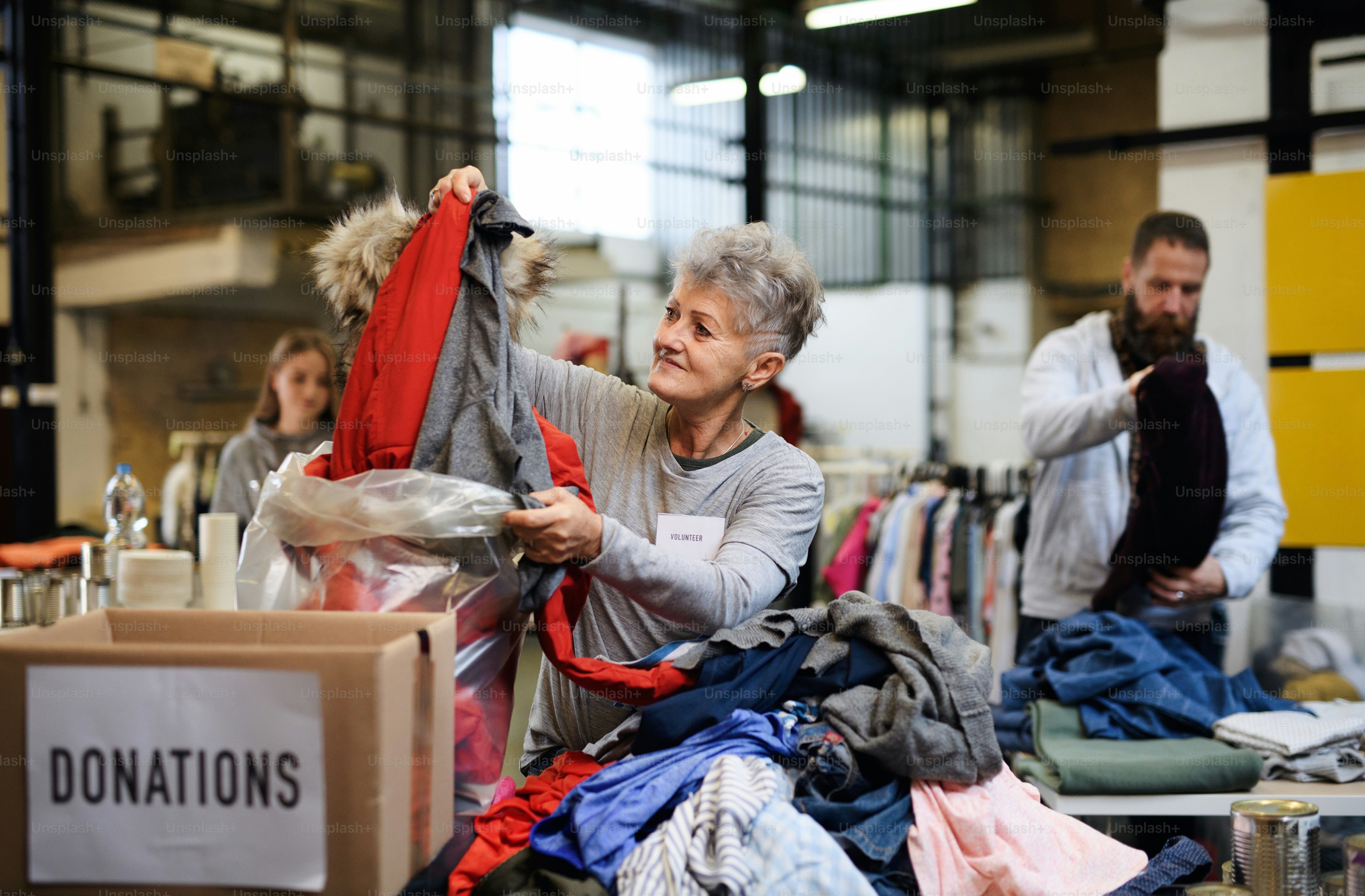 Portrait of volunteers sorting out donated clothes in community charity ...