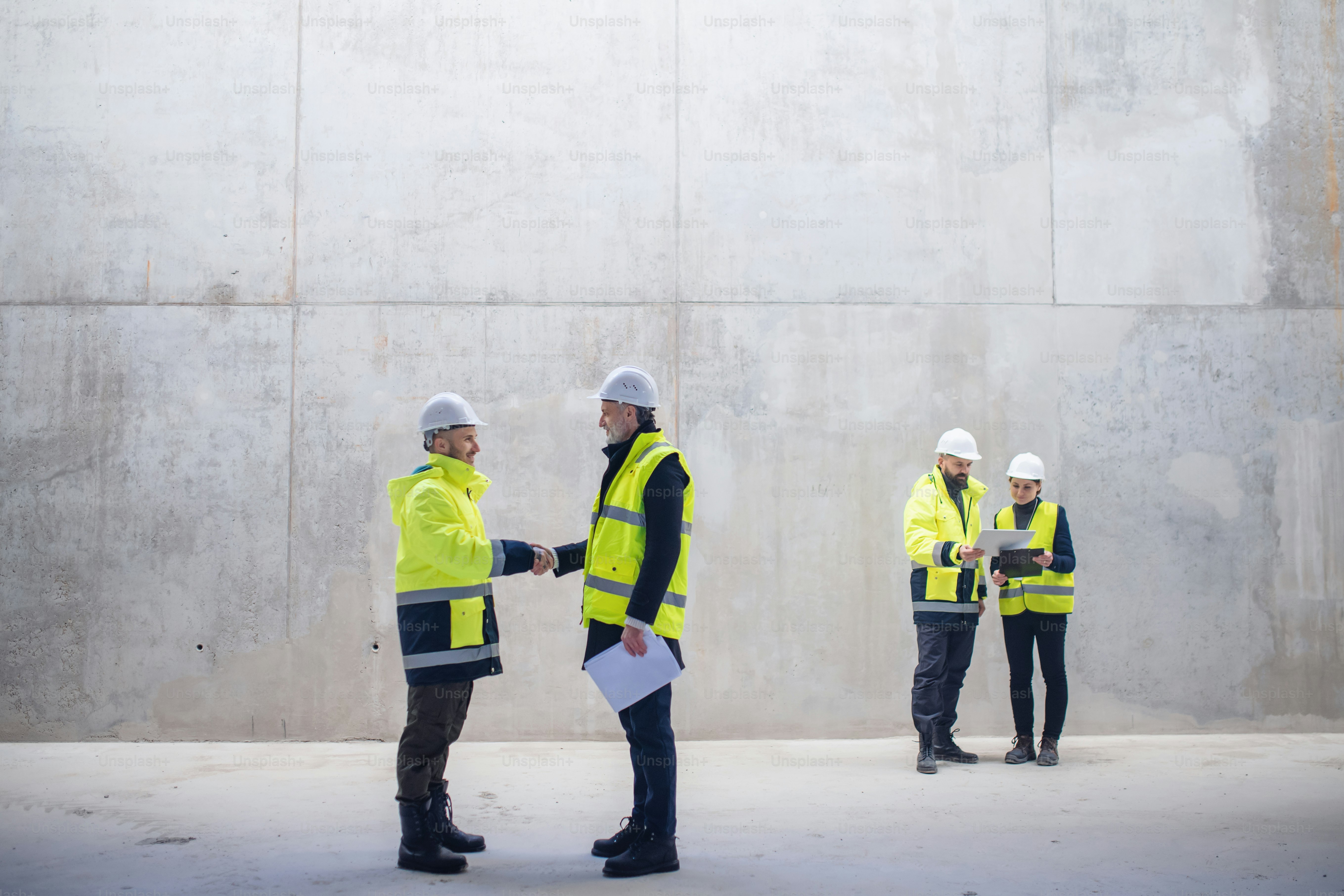 A group of engineers standing on construction site, shaking hands. Copy ...